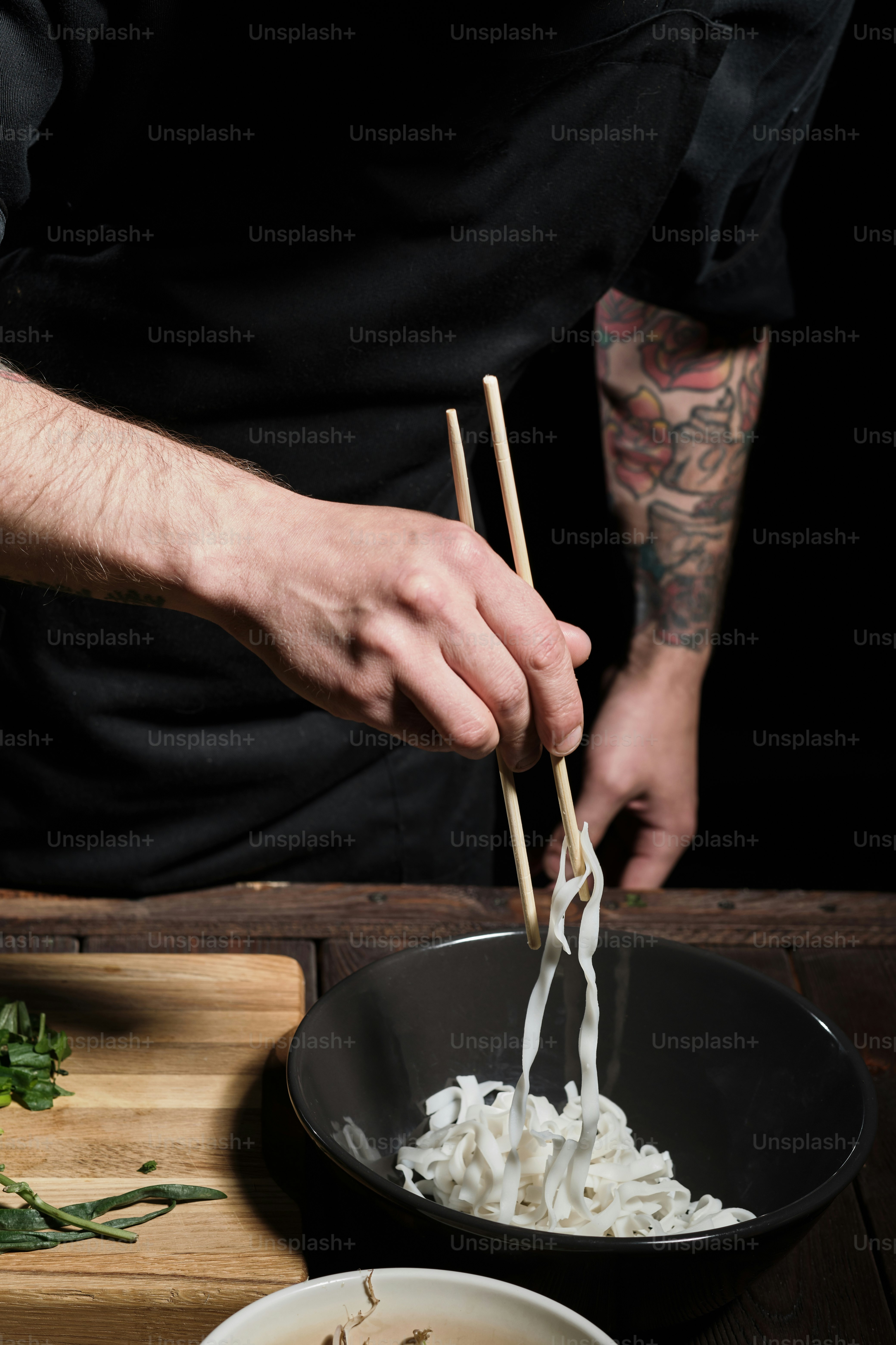 Close up of chef's hands picking noodles from the bowl, preparing asian ...