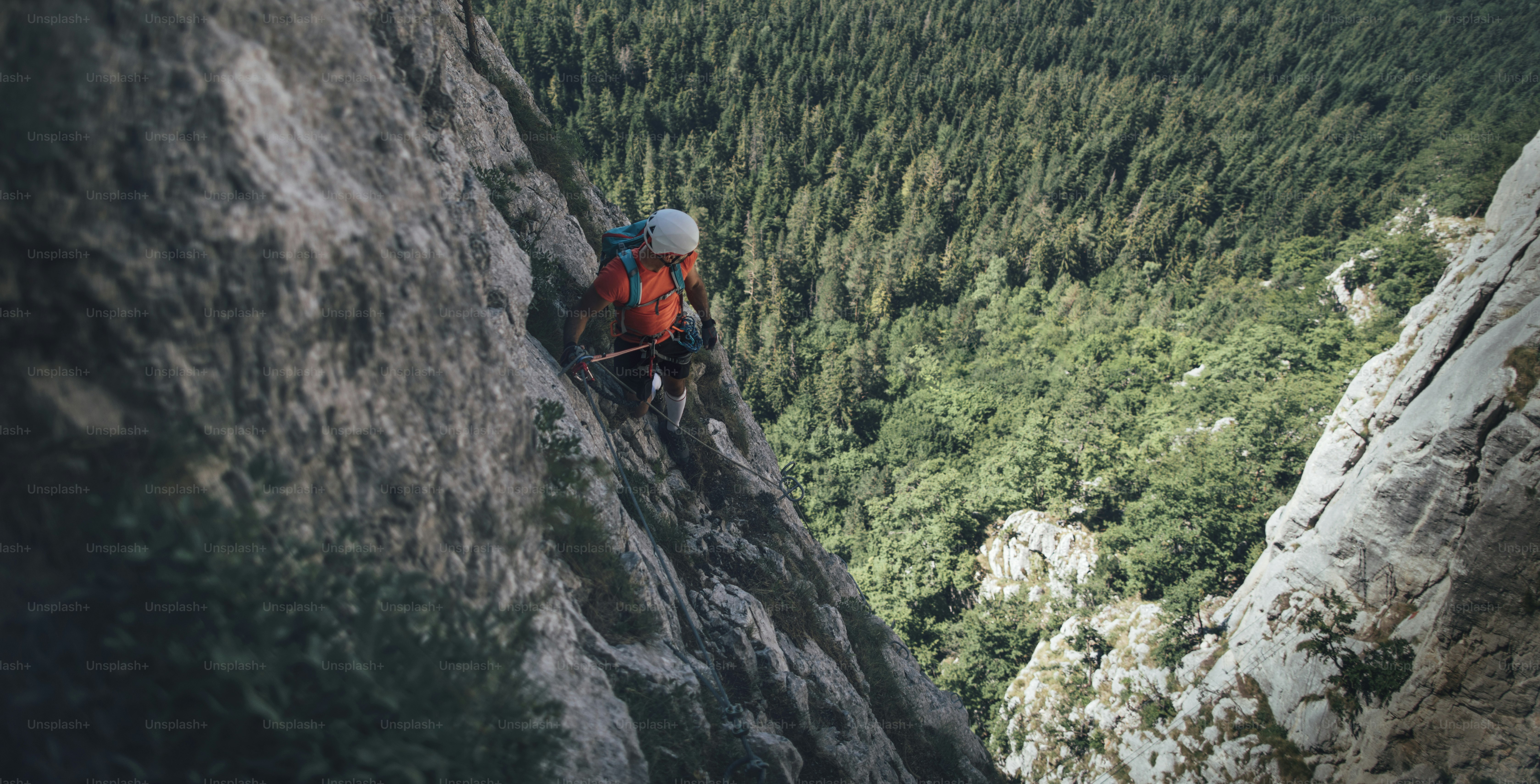 Climber on via ferrata trail, crossing a steep mountain edge. photo ...