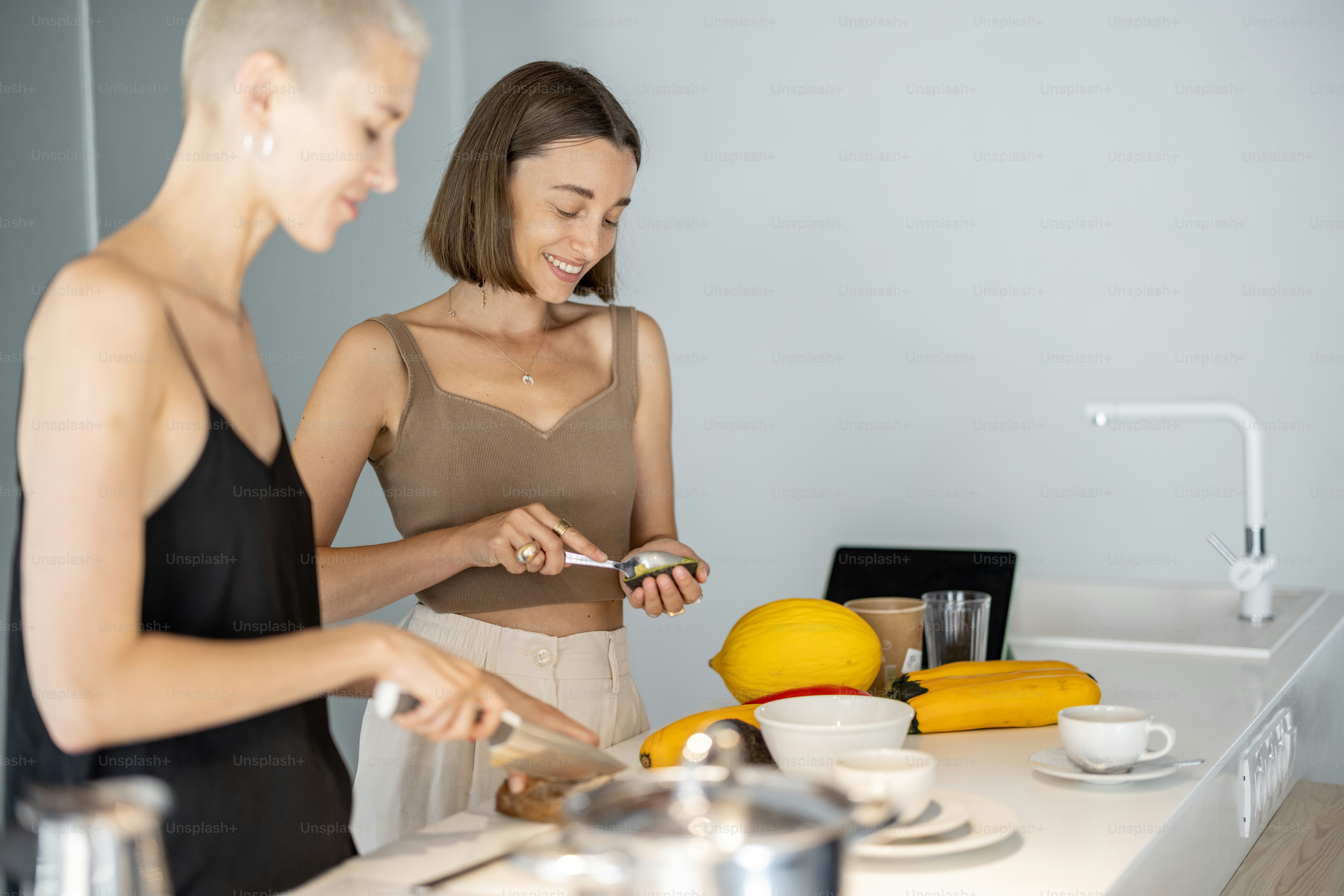 Joven pareja de lesbianas cocinando comida vegetariana saludable en una ...