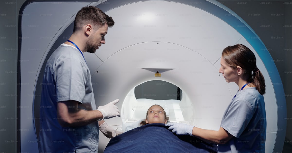 Mri 스캔 기계에서 검사하기 전에 작은 환자와 상담하는 두 명의 방사선 전문의 중 한 명 사진 Unsplash의 작다 이미지