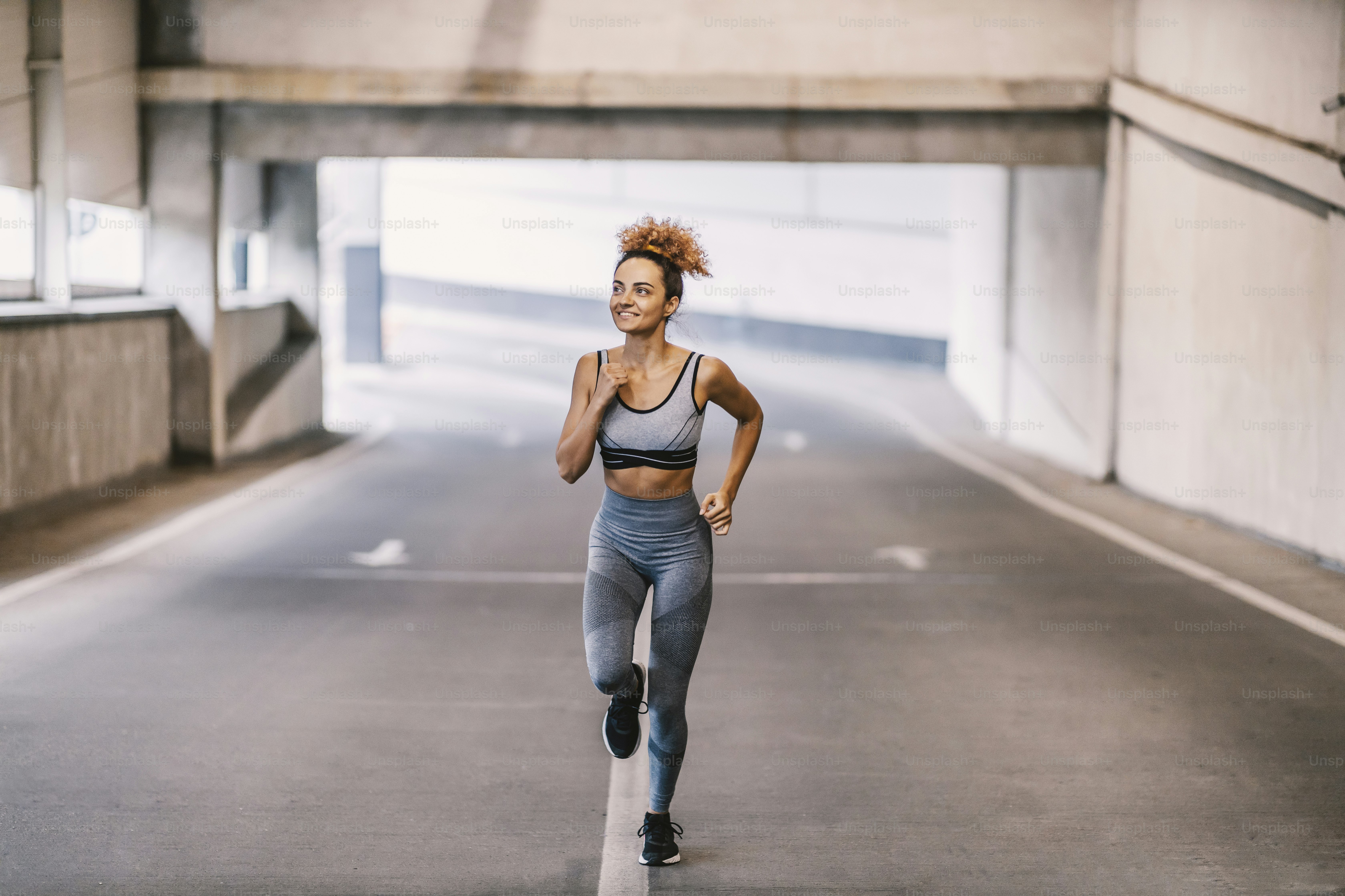 A happy urban sportswoman is running in the garage and preparing for a ...