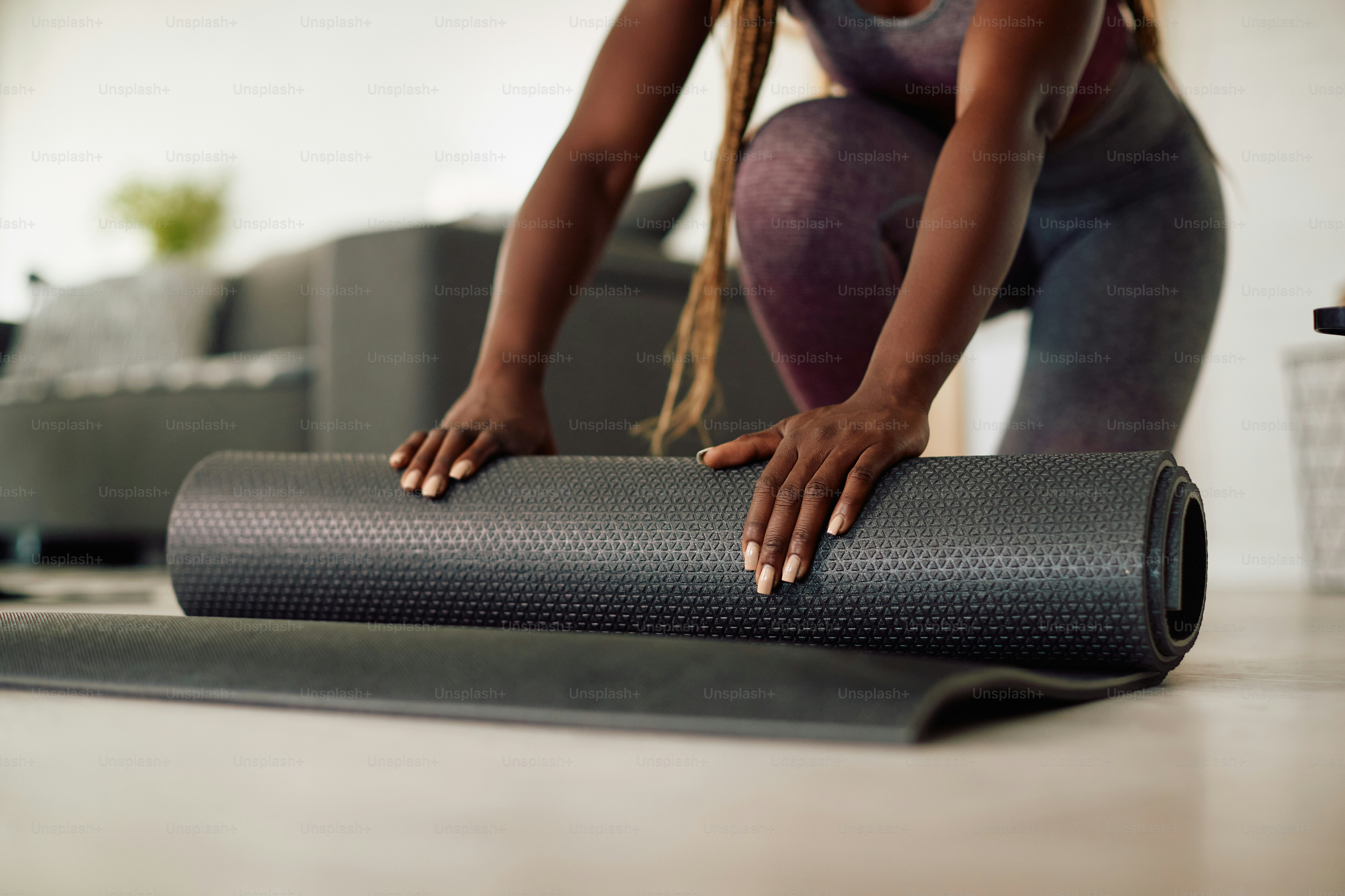 Close-up of black sportswoman unrolling her exercise mat while ...