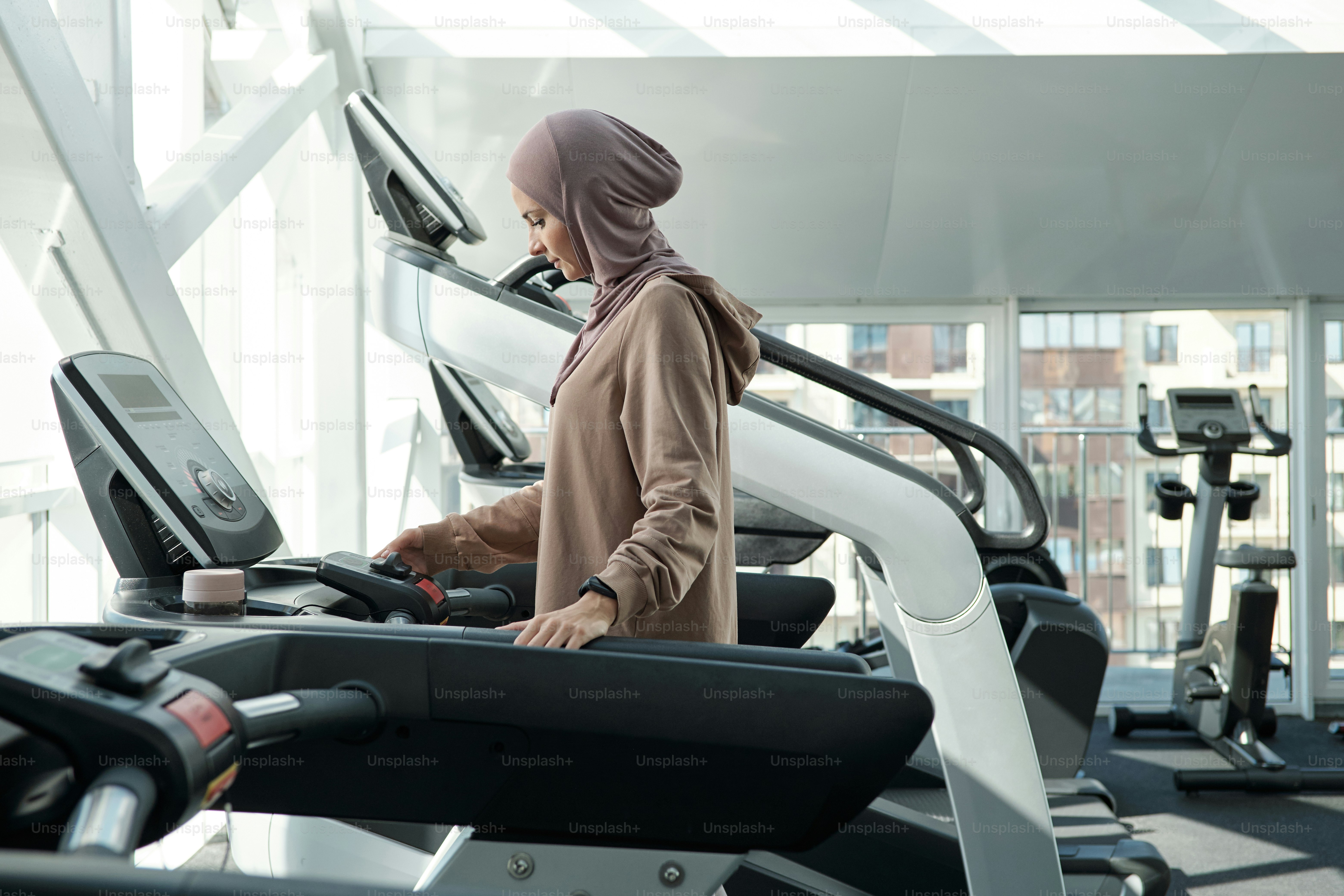 Horizontal long shot of modern Muslim woman wearing hijab exercising in ...