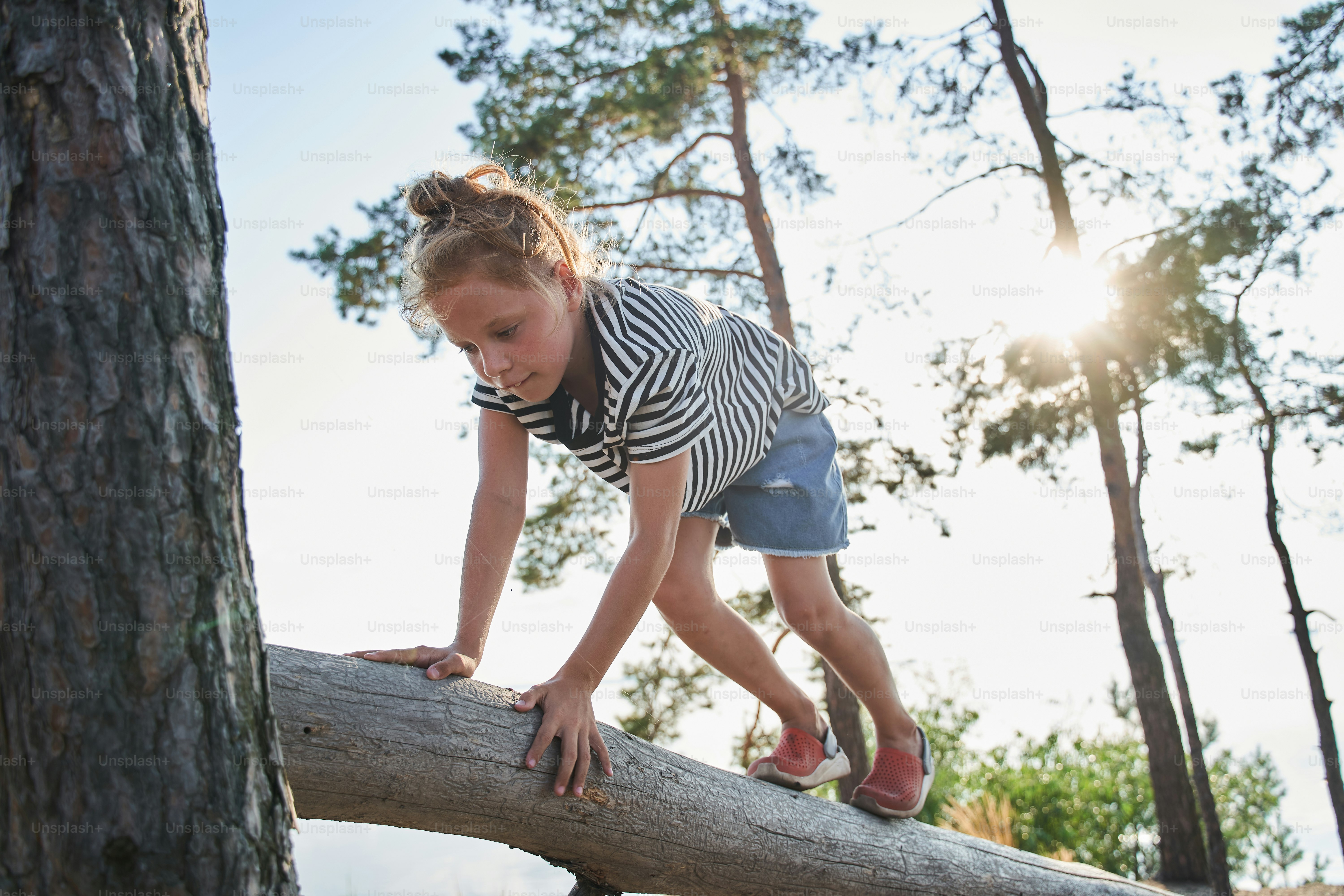 Glückliches Kind, das im Wald spielt und auf den Baum klettert. Süßes ...