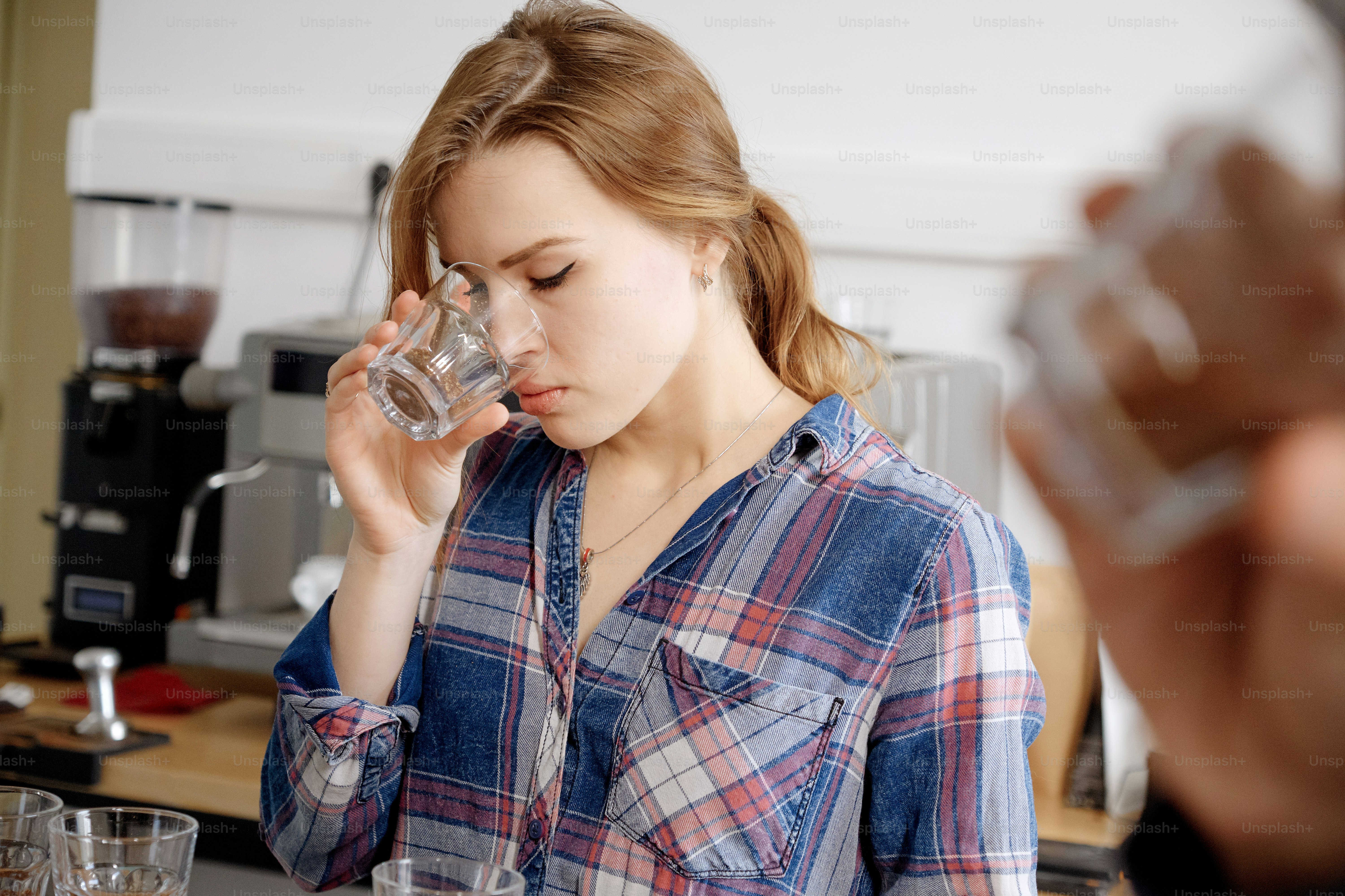 Portrait in selective focus of young female barista examining cups with ...