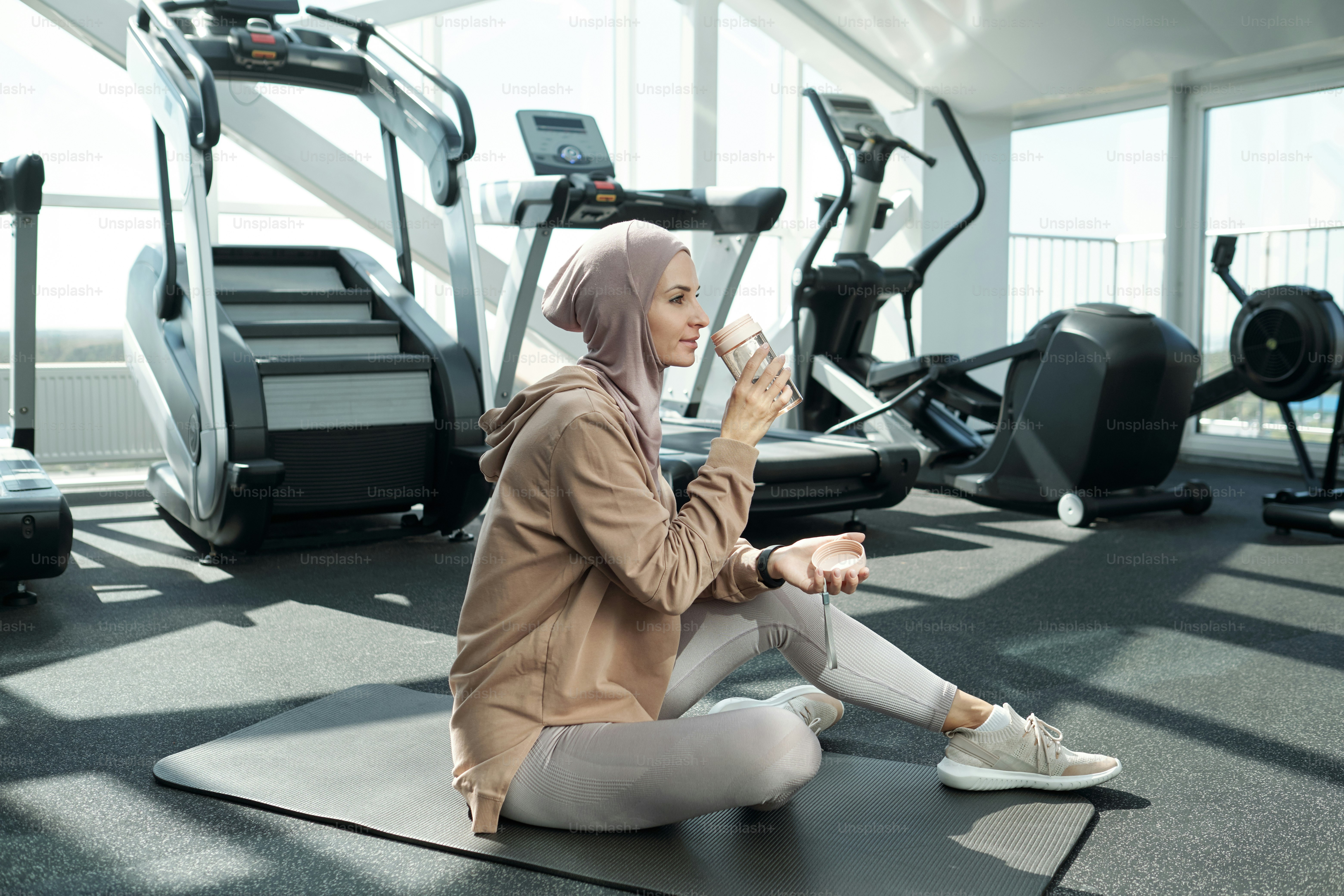Horizontal long shot of modern Muslim woman wearing hijab exercising in ...