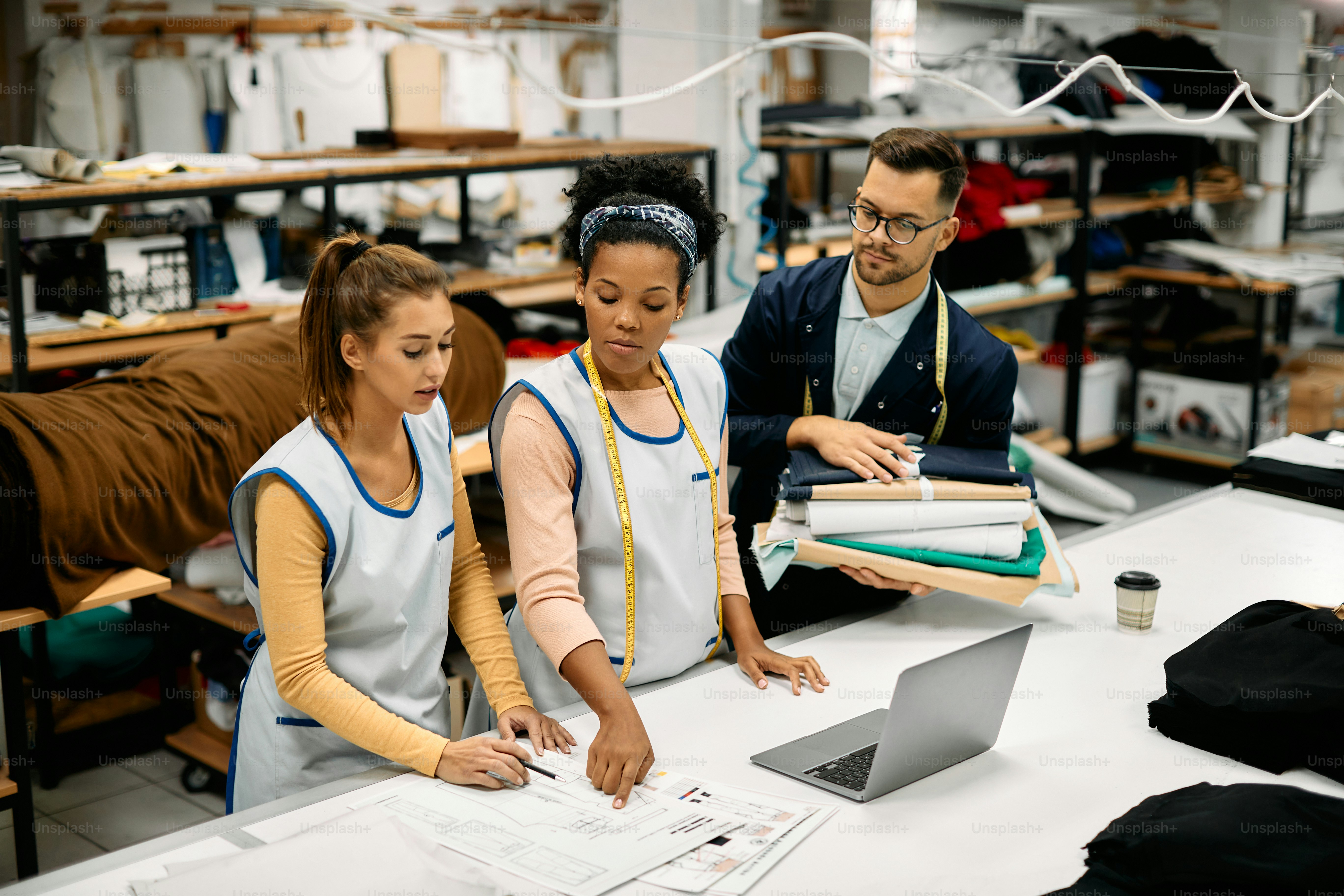 Team of tailors analyzing sketches while working on new clothing design in a studio. photo ...