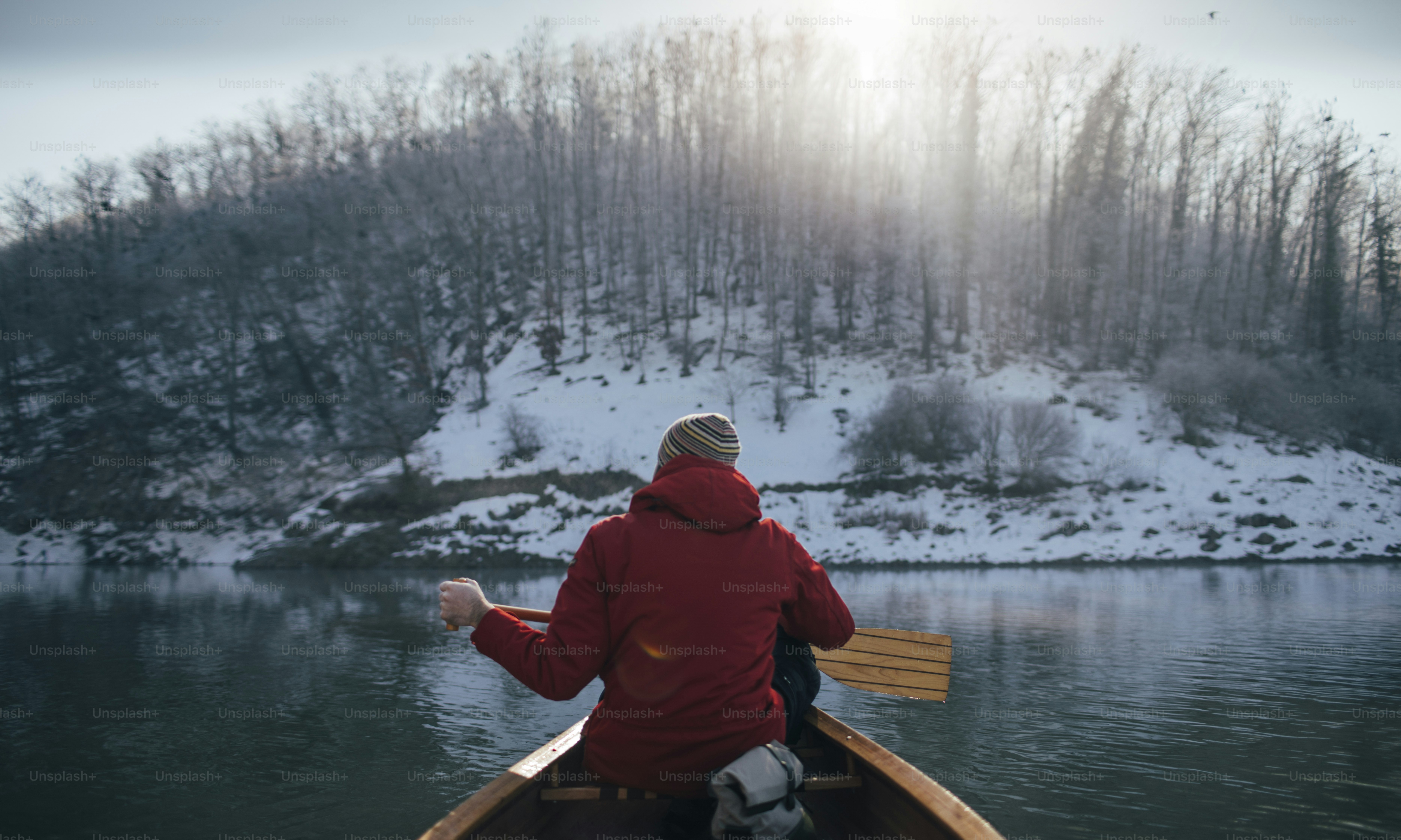 Rear view of man paddling on winter canoe ride. photo – Healthy ...