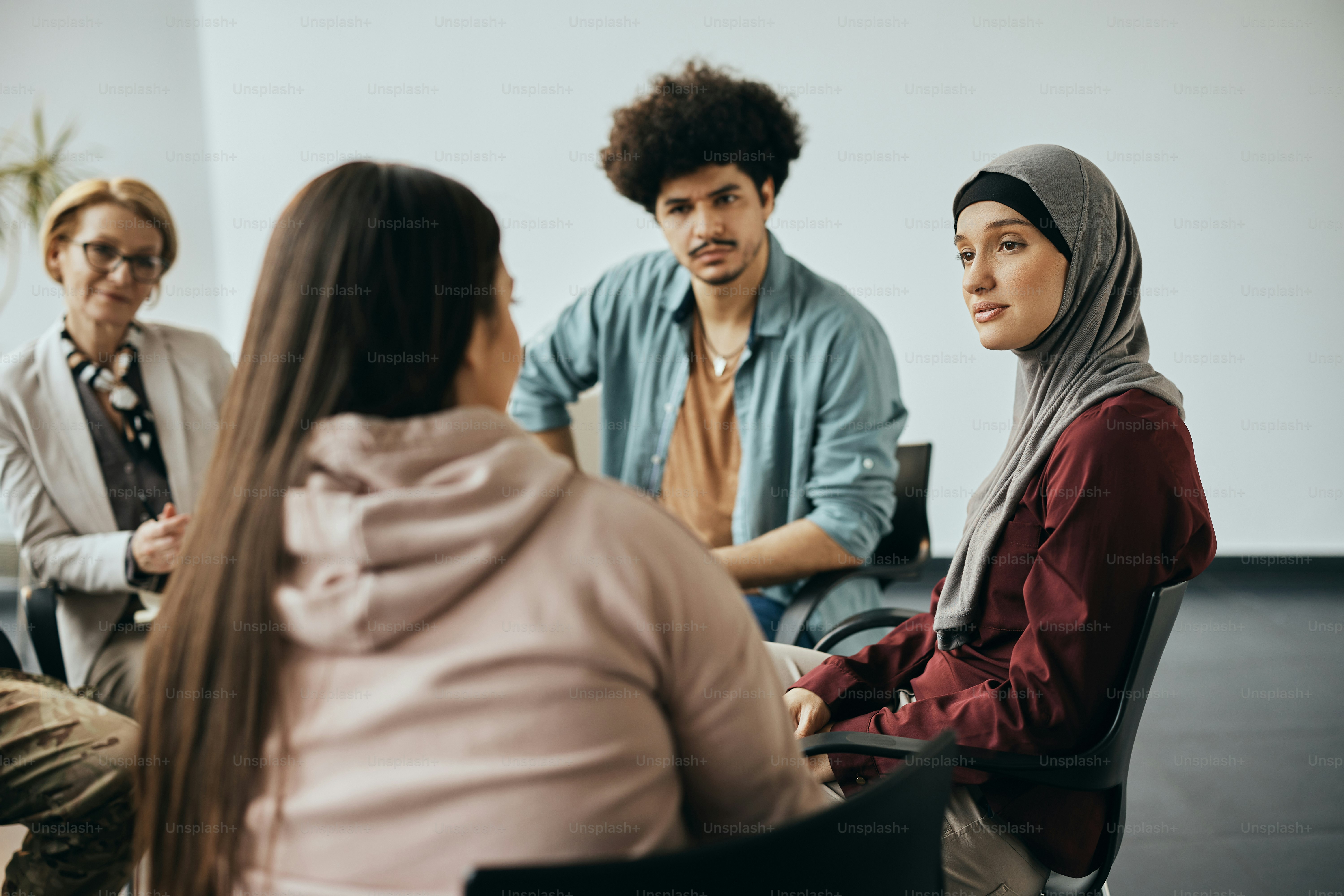 Young Muslim woman talking to group therapy members during their ...
