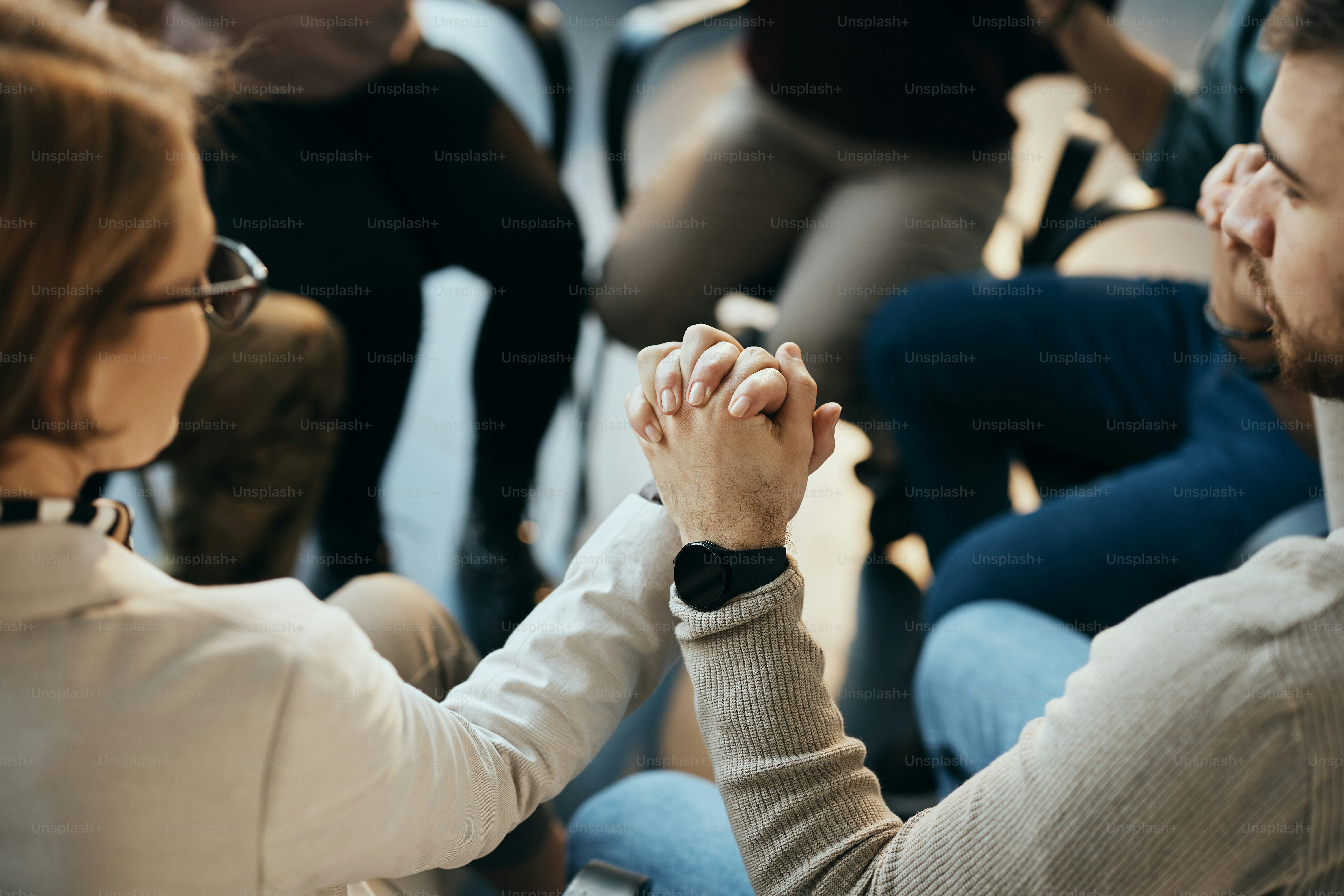 Close-up of people holding hands and supporting each other during group ...