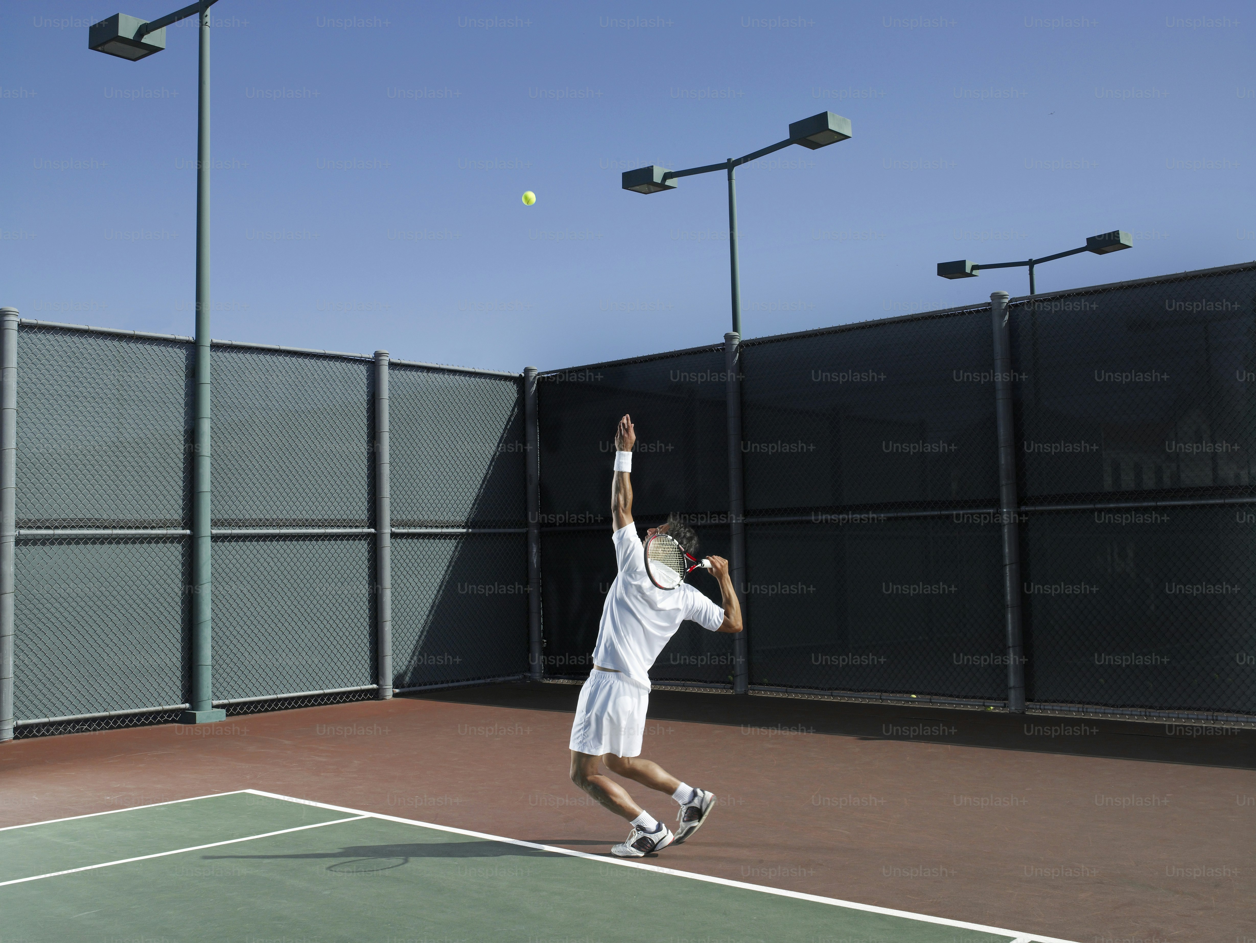 A man holding a tennis racquet on a tennis court photo – Tennis Image ...