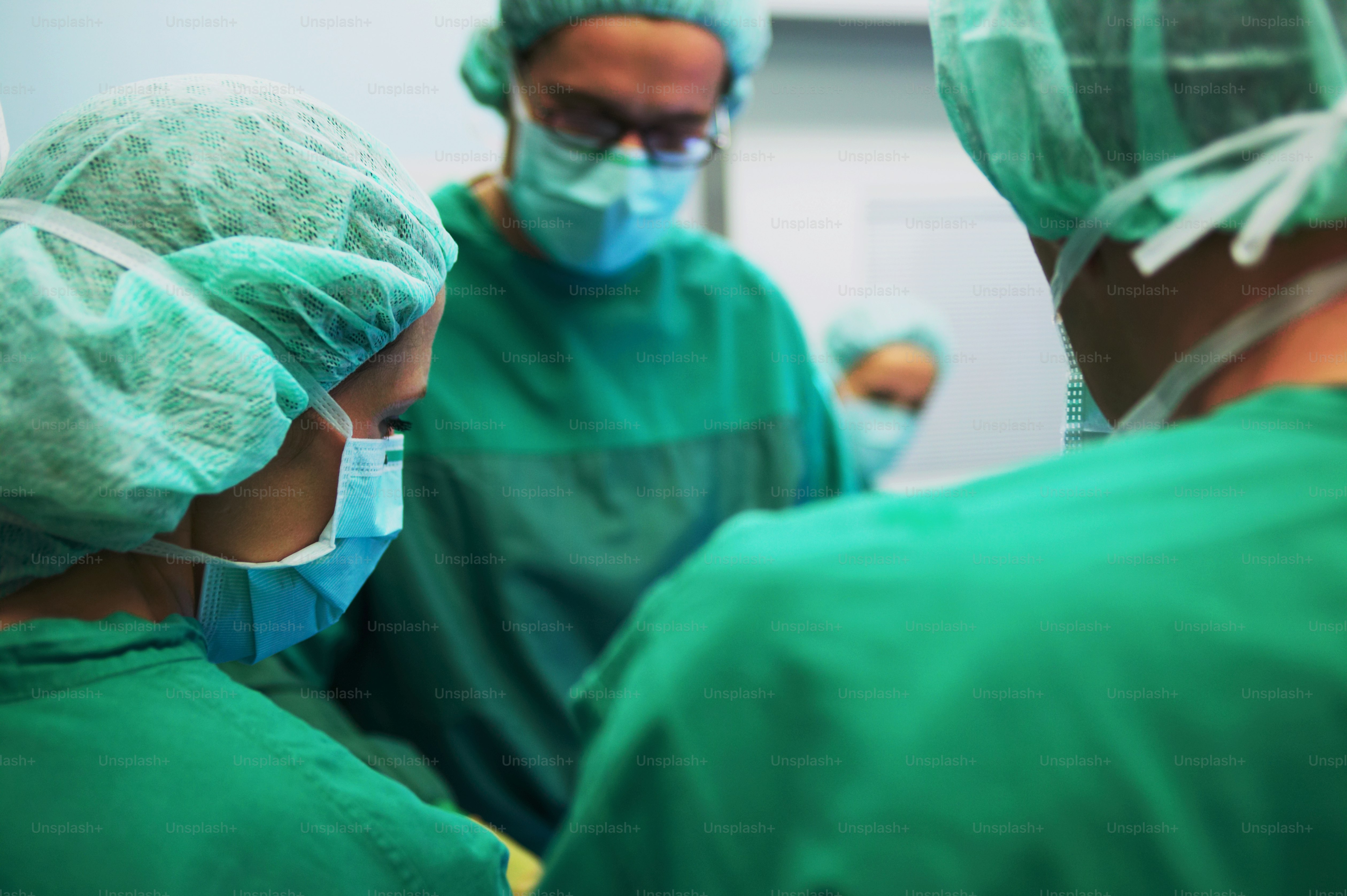 A group of surgeons in green scrubs and masks photo – Surgical mask ...