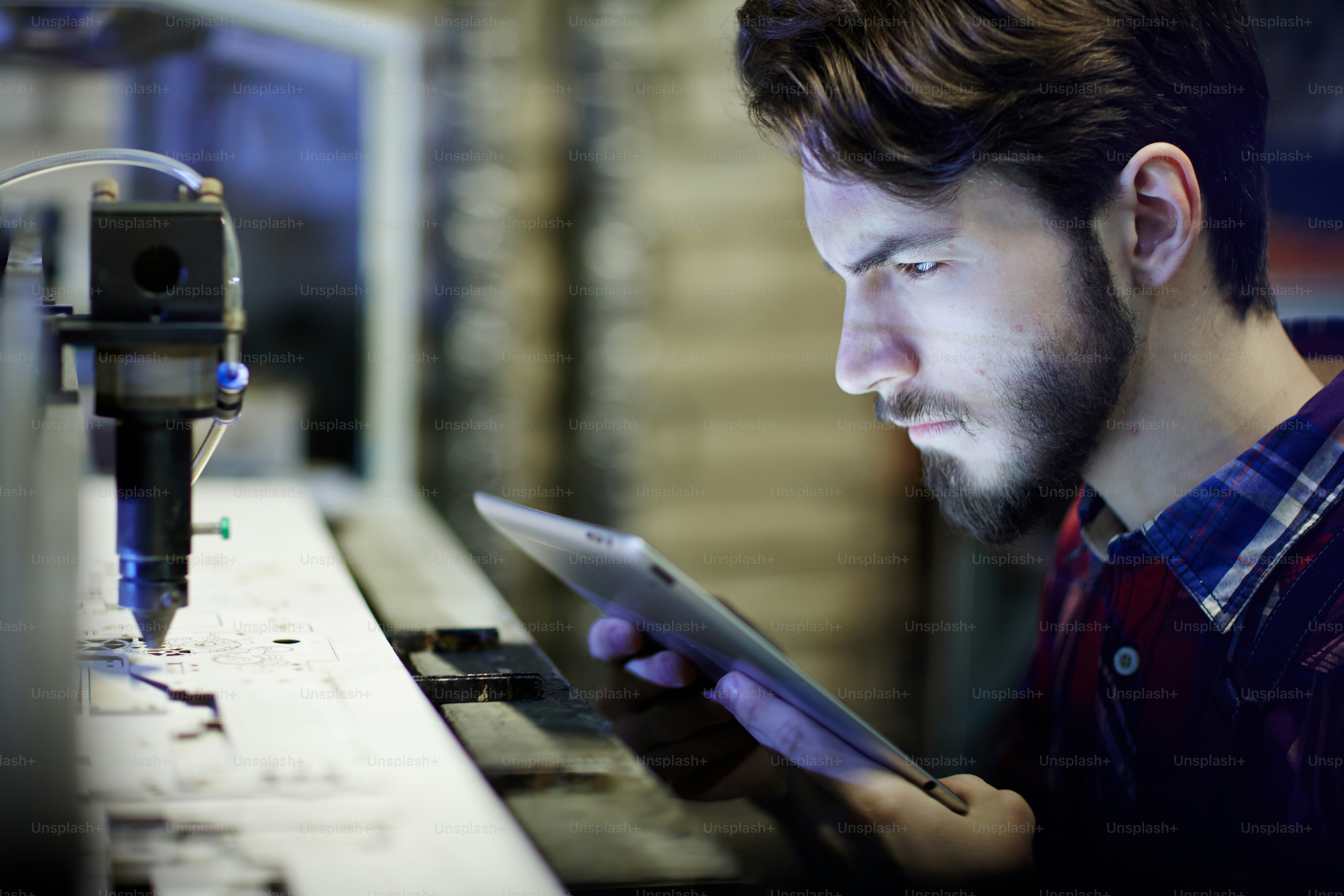 Side view portrait of modern factory worker using digital tablet to ...