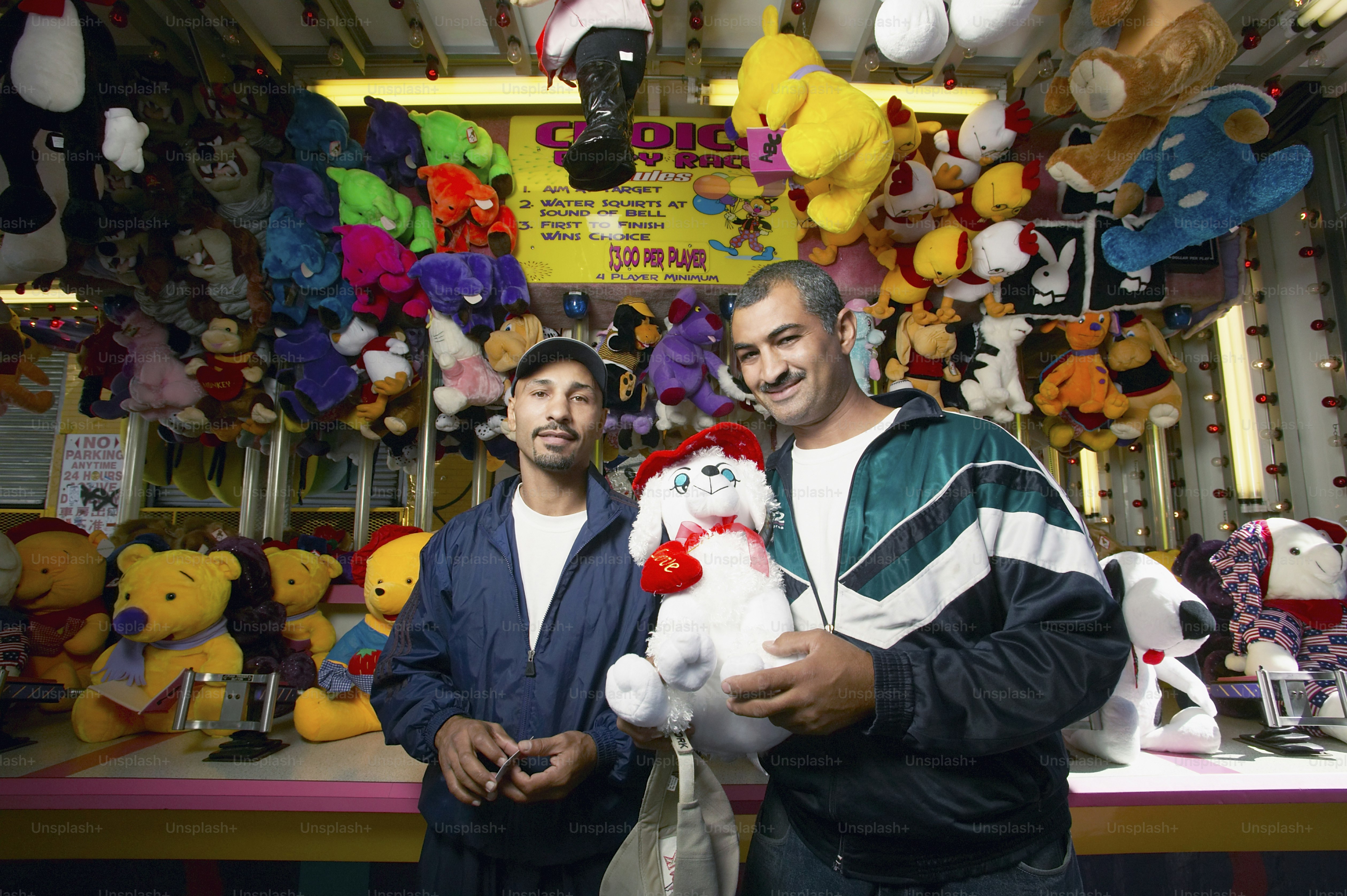 Two men standing in front of a display of stuffed animals photo – Toy ...
