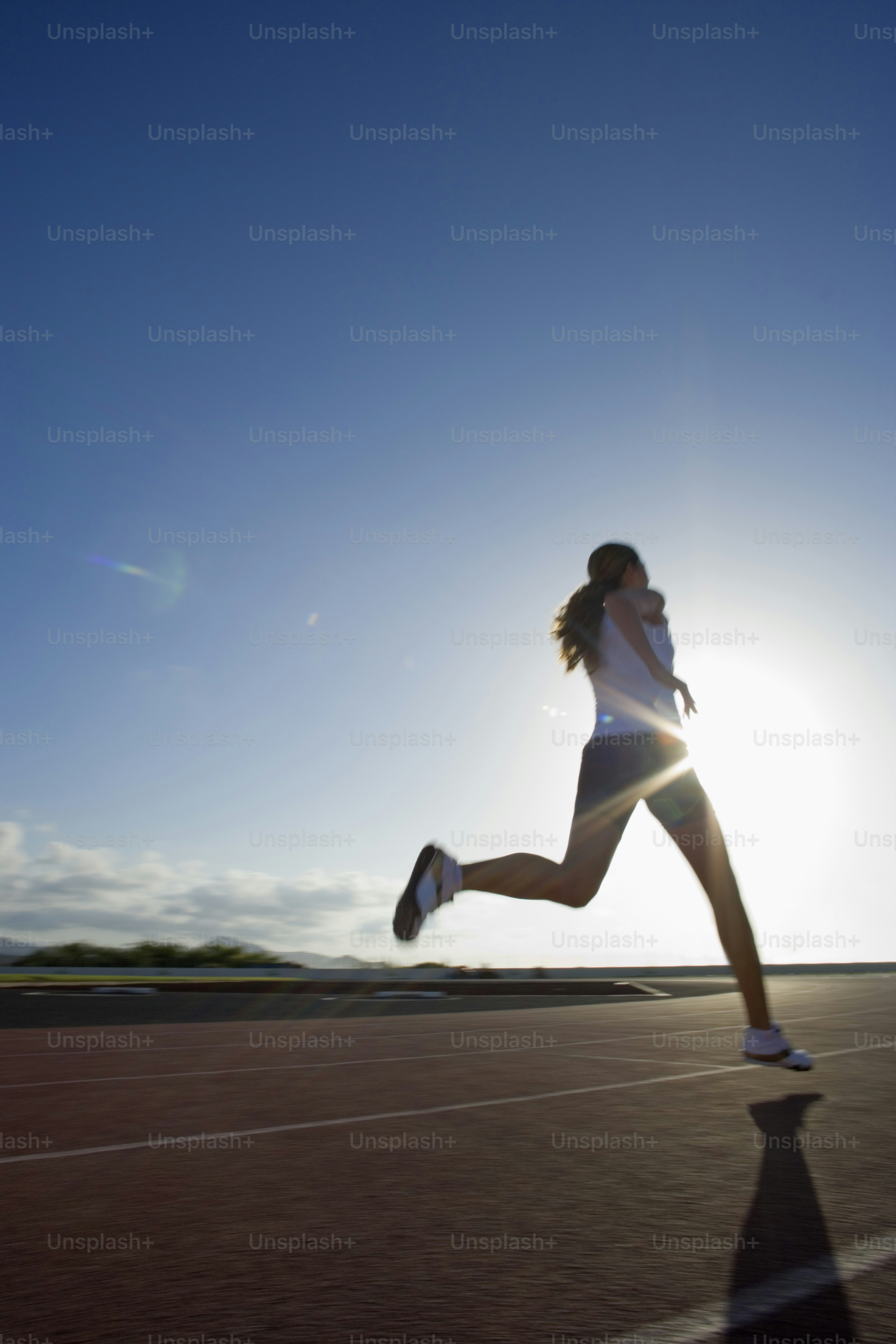 A woman running on a road with the sun in the background photo ...