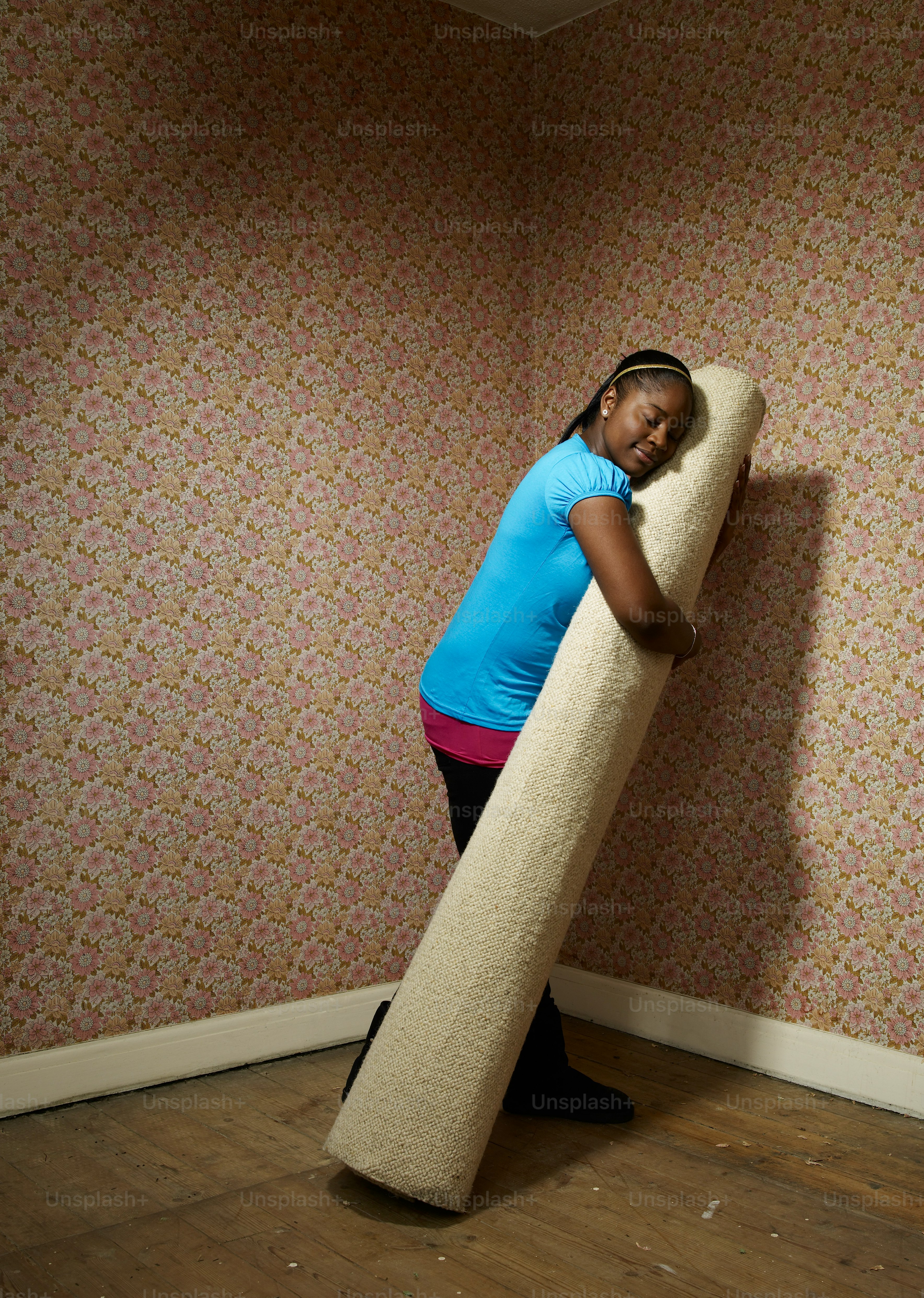 A woman standing in a room holding a large pillow photo – African ...