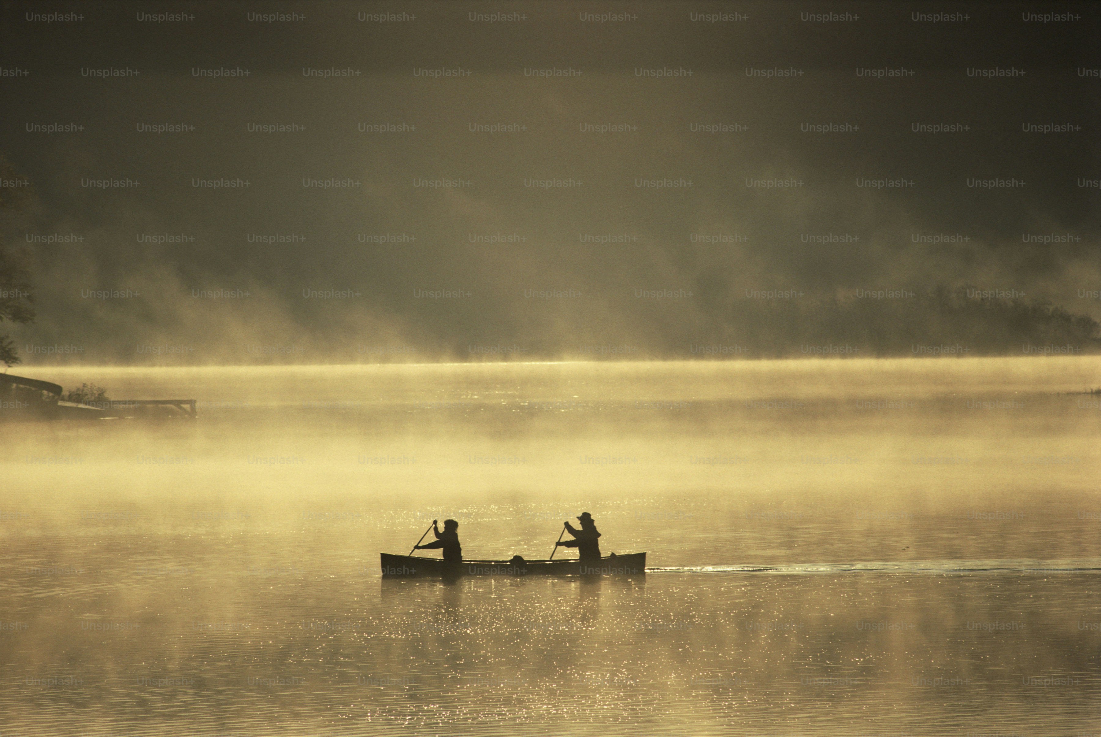 Deux personnes dans une barque à rames sur un lac brumeux photo – Image ...