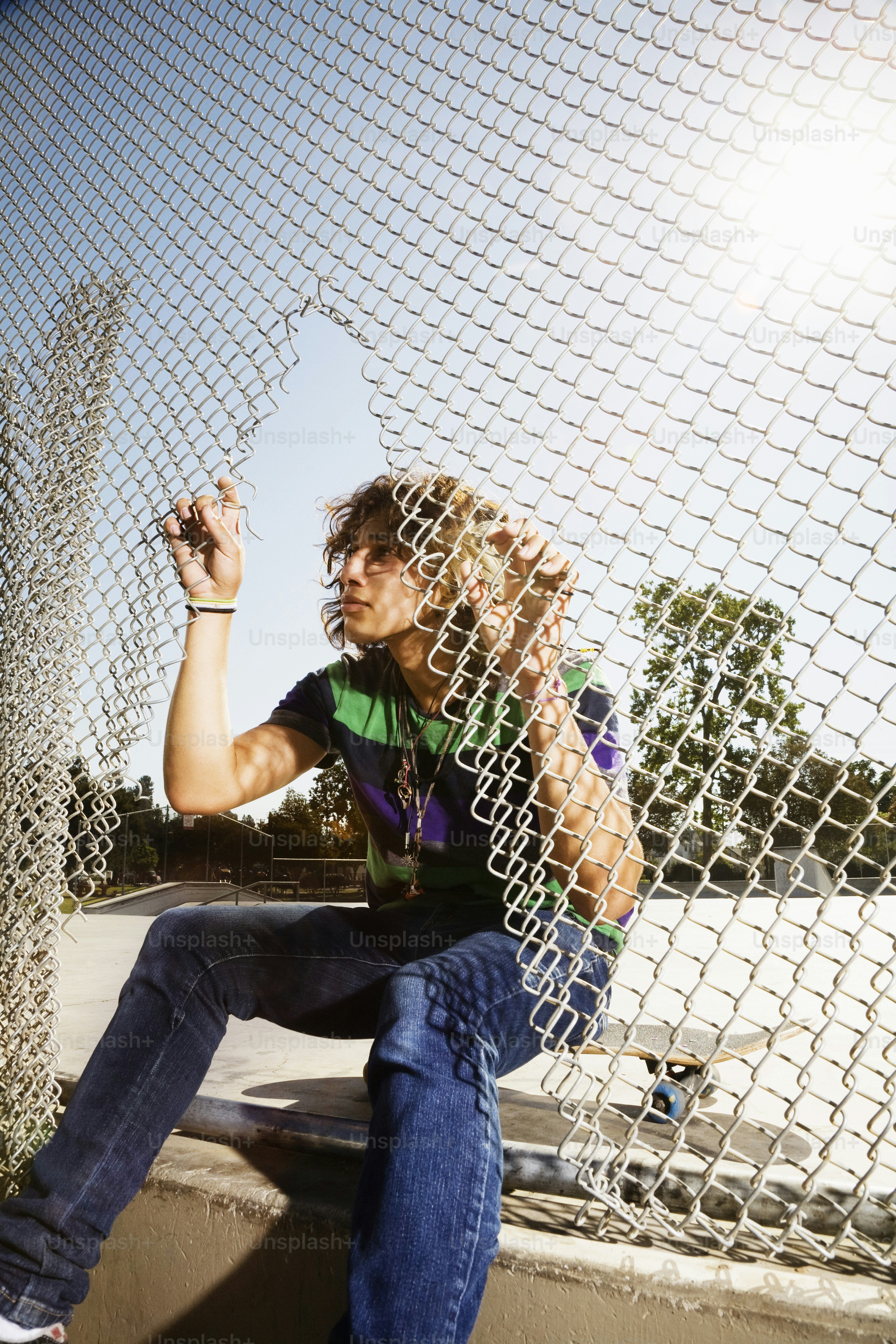 A man sitting on a ledge with his hand in the air photo – Chainlink ...