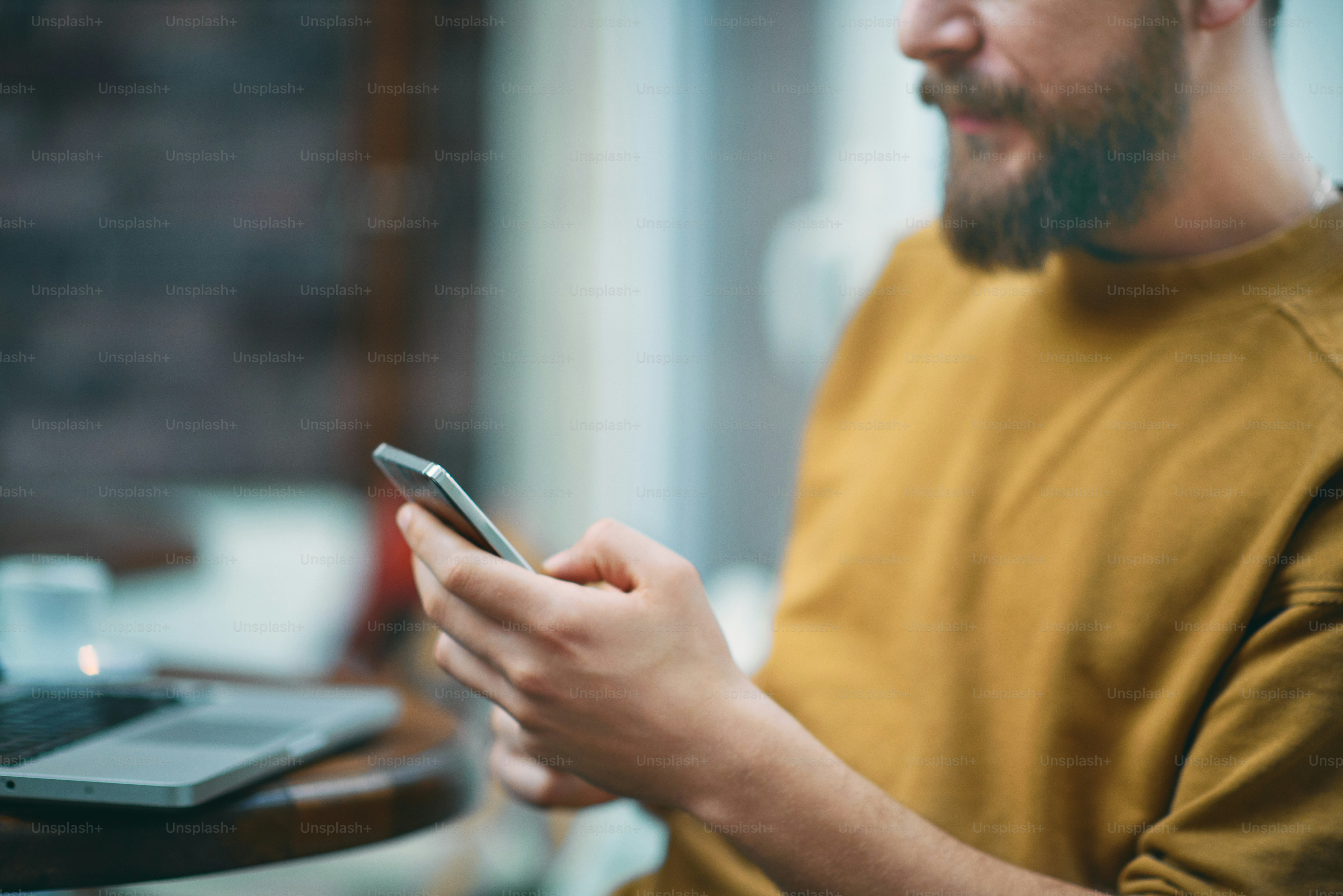 Young man sitting in cafe and using smart phone. photo – Table Image on ...