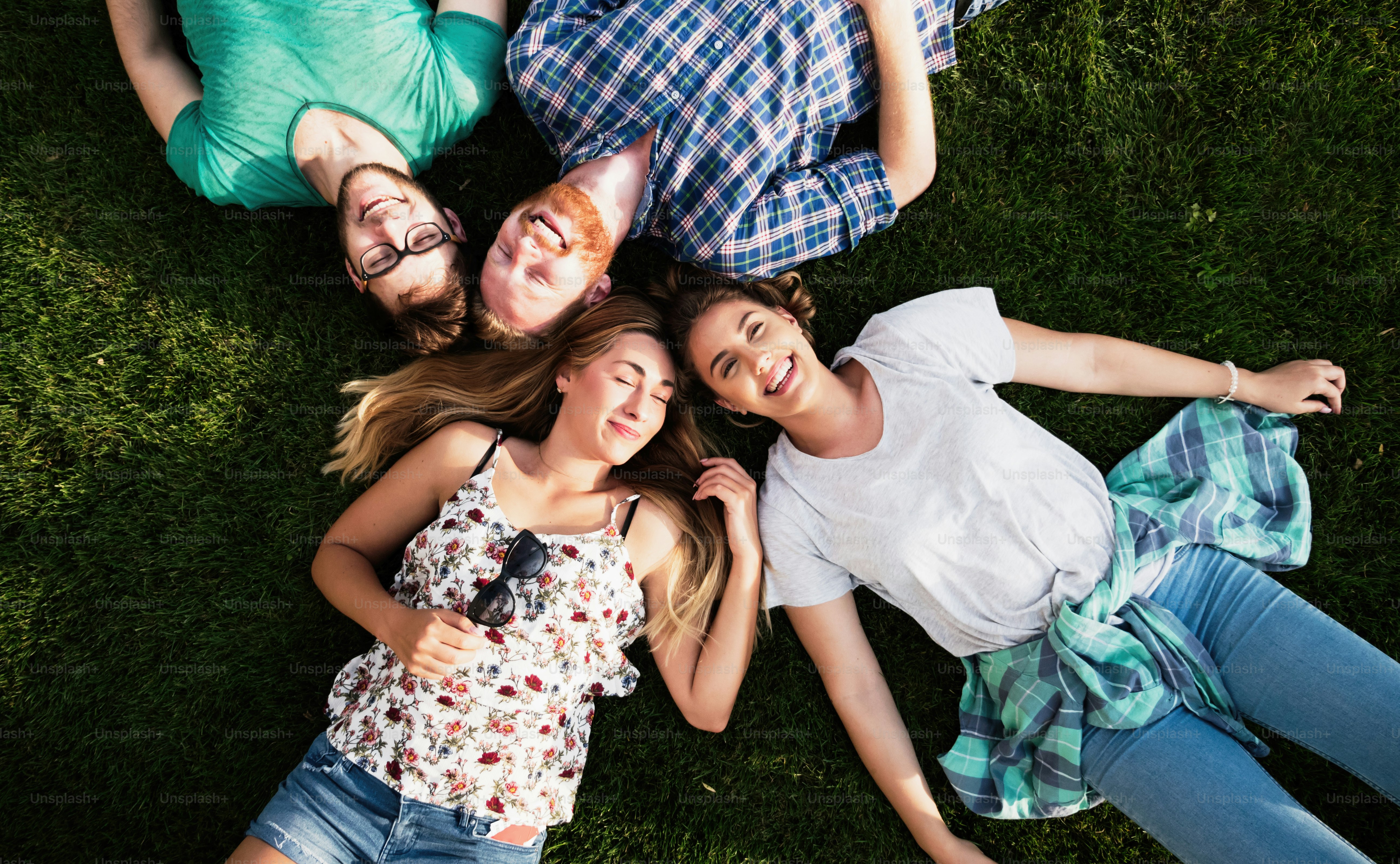 Happy joyful students lying in grass while and smiling photo – Portrait ...