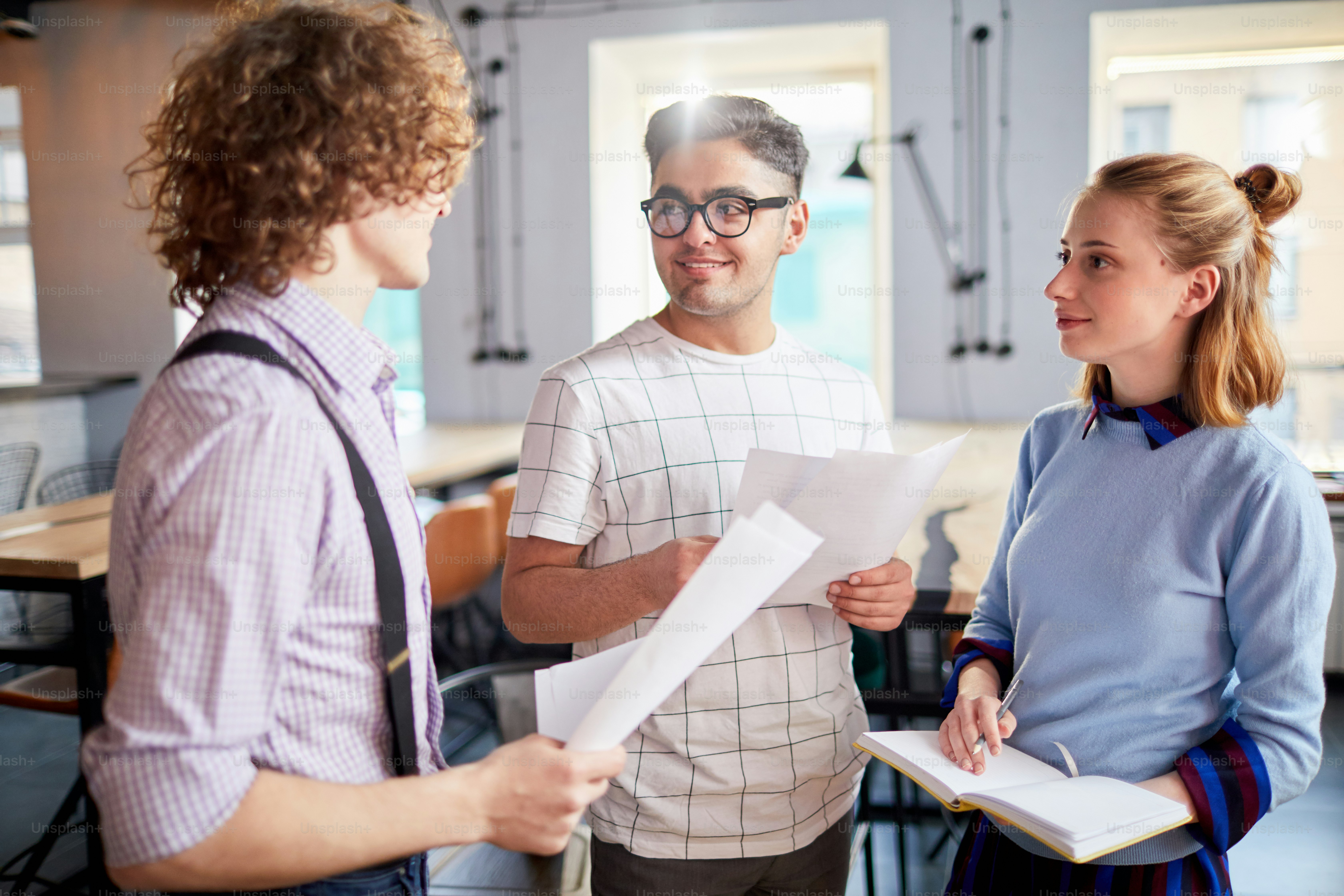Three busy young employees having discussion of working points at ...
