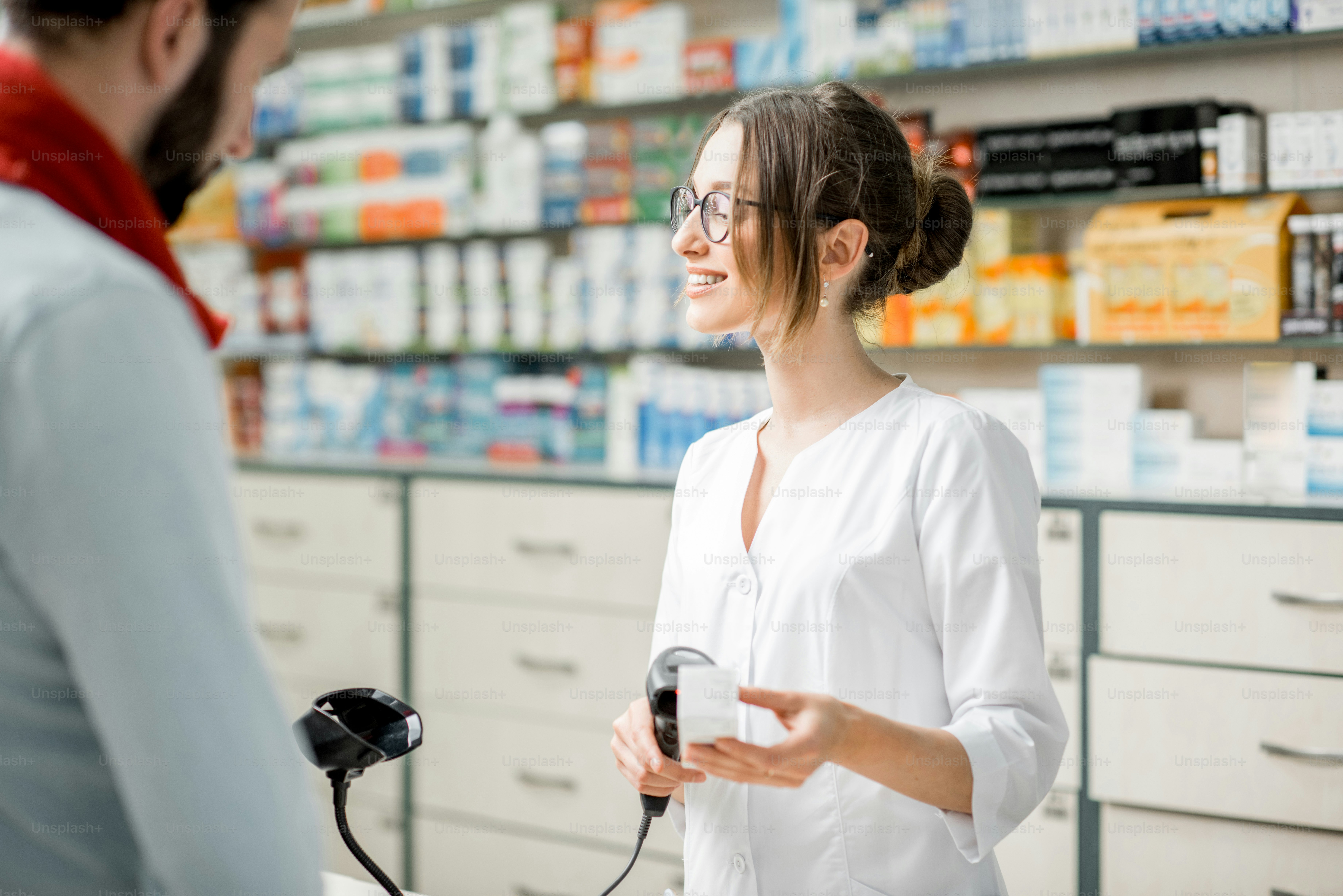 Young woman pharmacist selling medications standing with male client at ...
