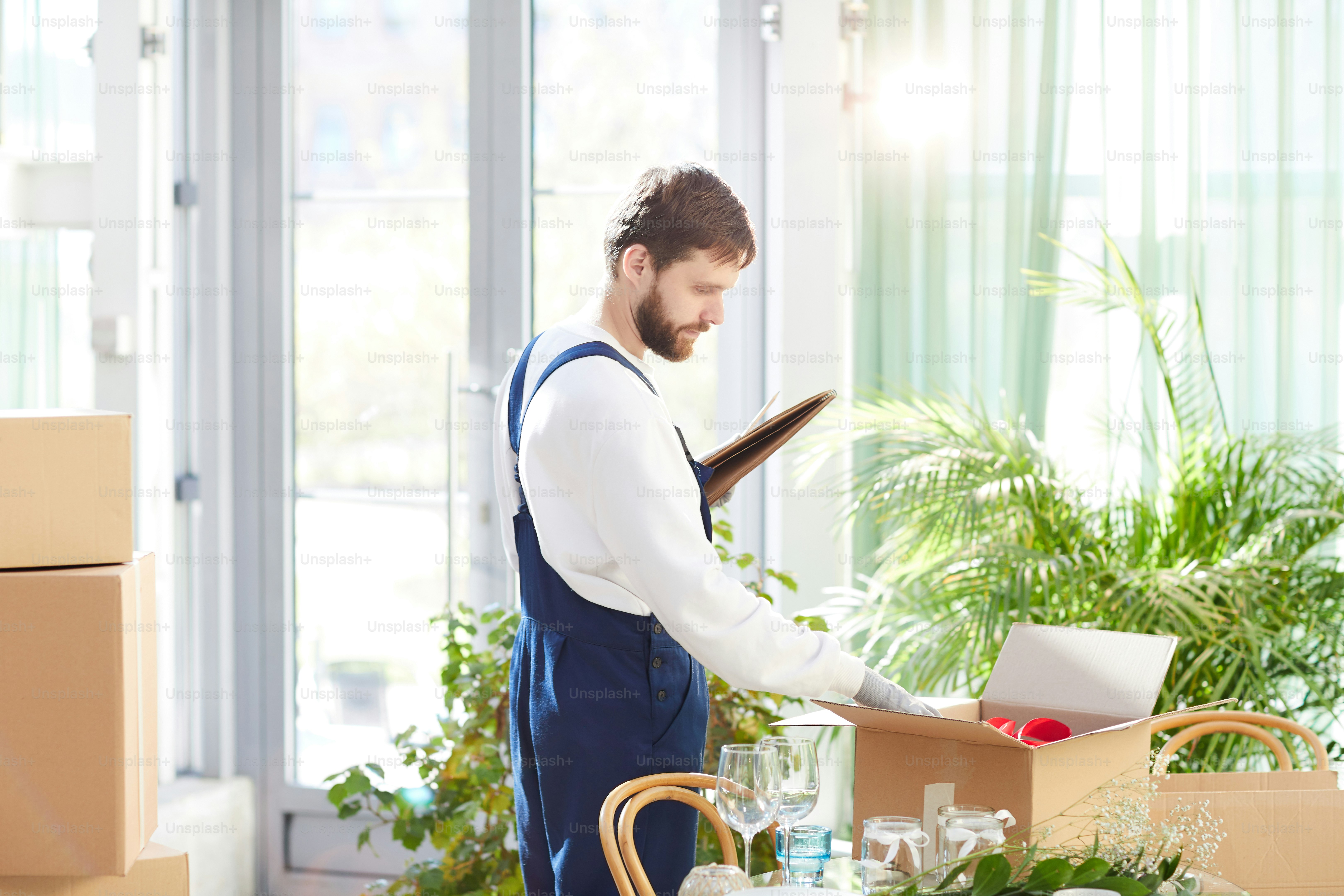 Serious concentrated handsome male moving company worker in uniform ...