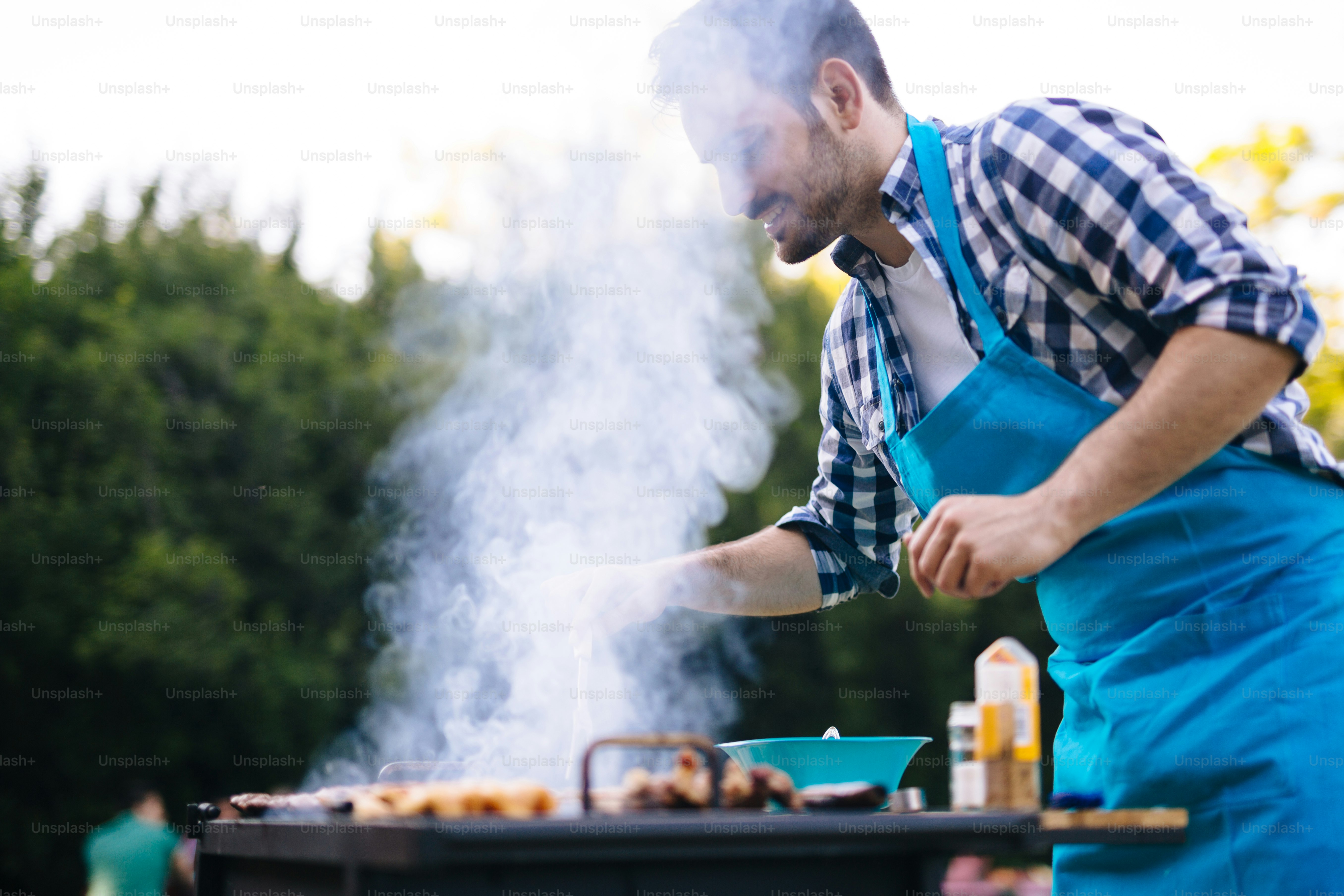 Handsome happy male preparing barbecue outdoors for friends photo ...