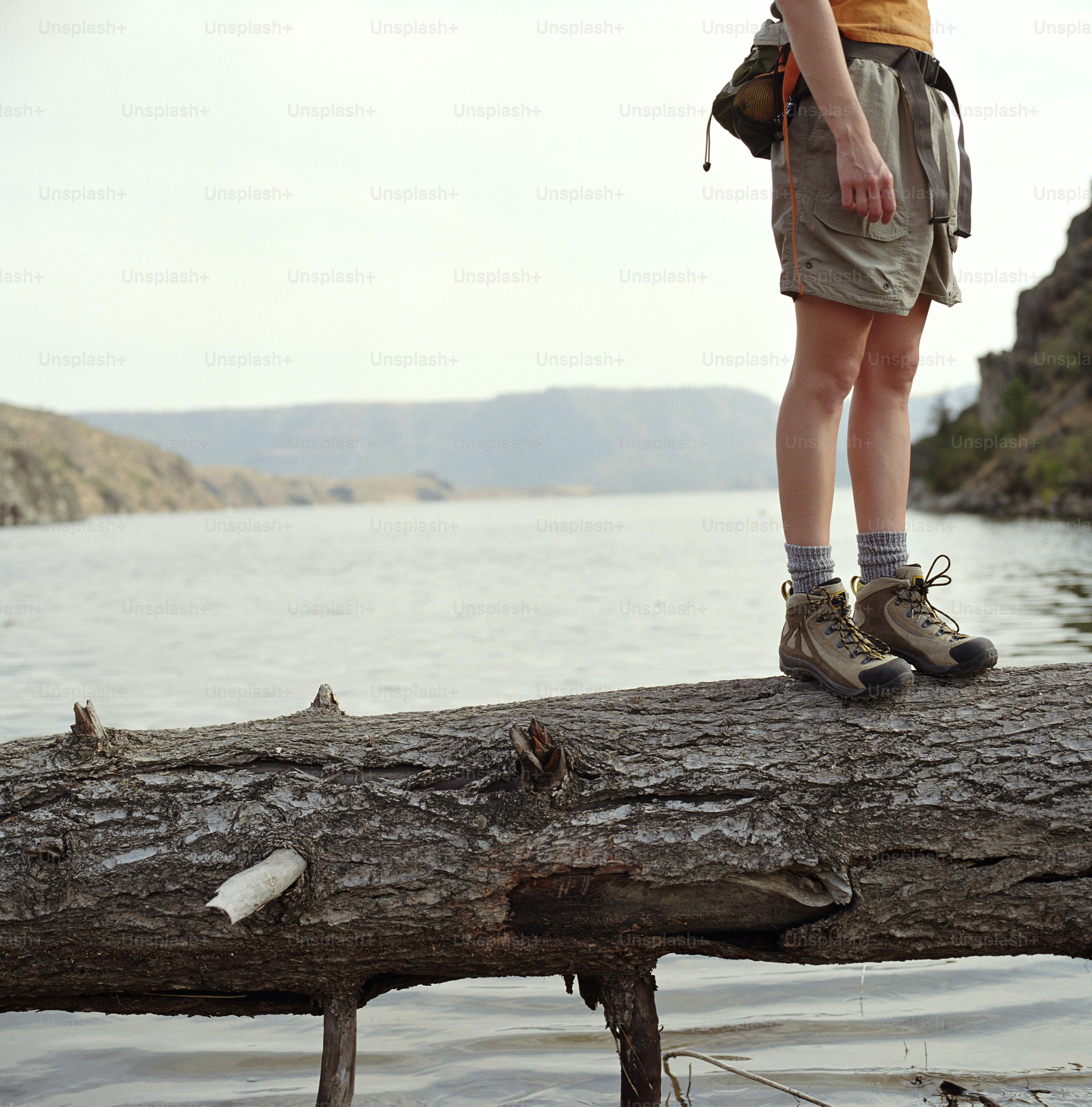 A person standing on a log over a body of water photo – Shorts Image on ...