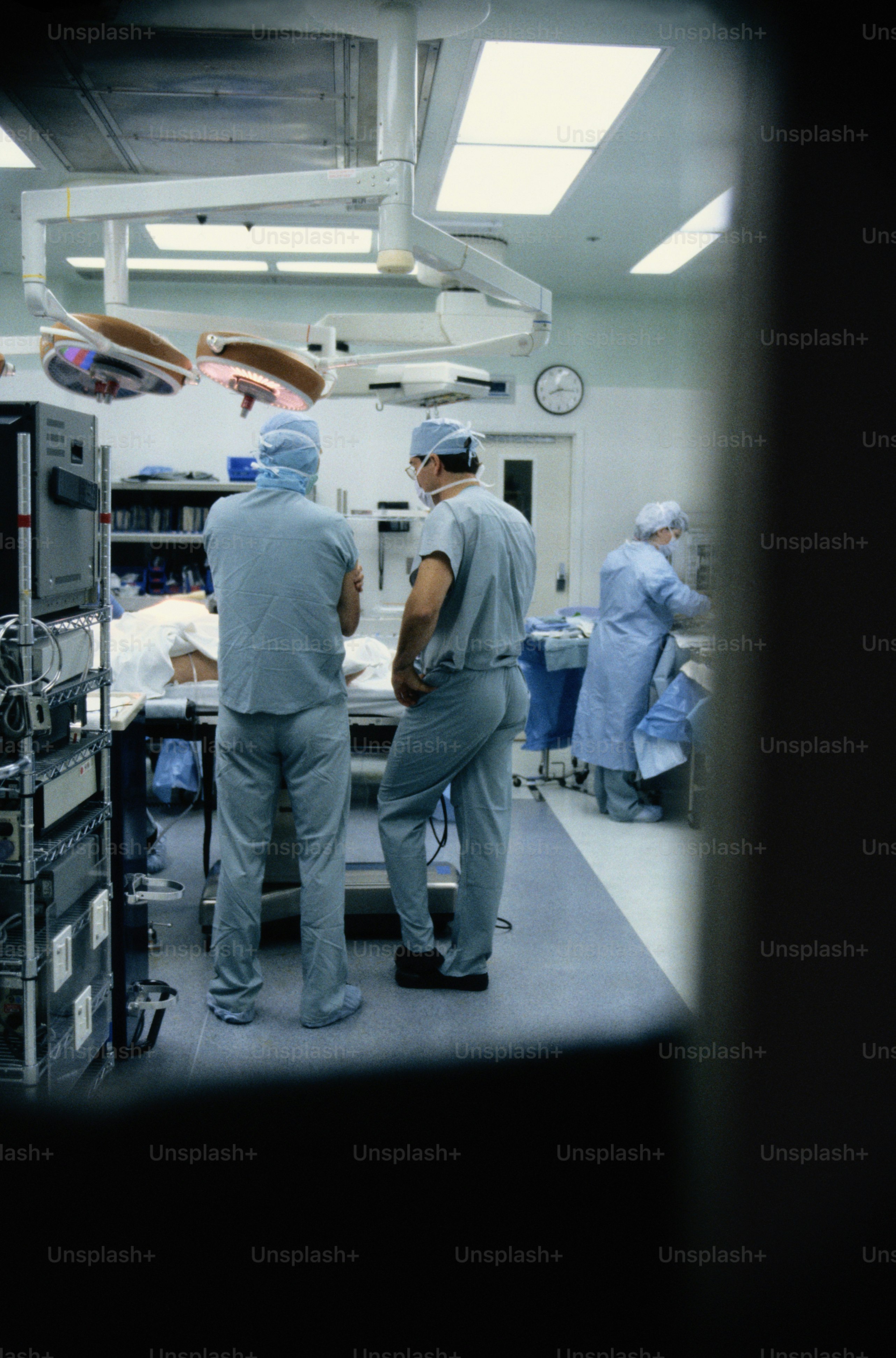 A group of doctors standing around a hospital room photo – Three people ...