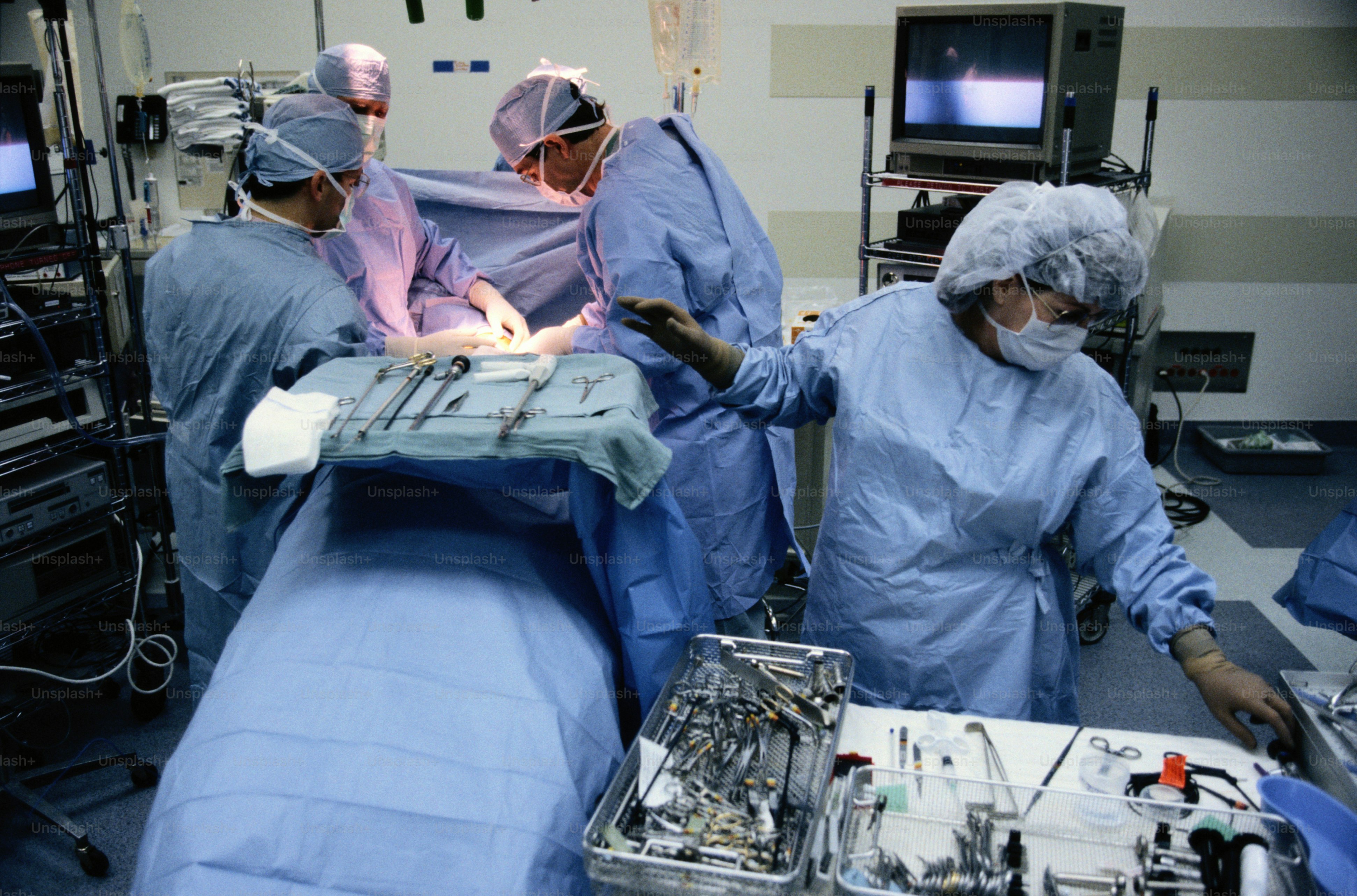 A group of doctors performing surgery in a hospital photo – Surgeon ...