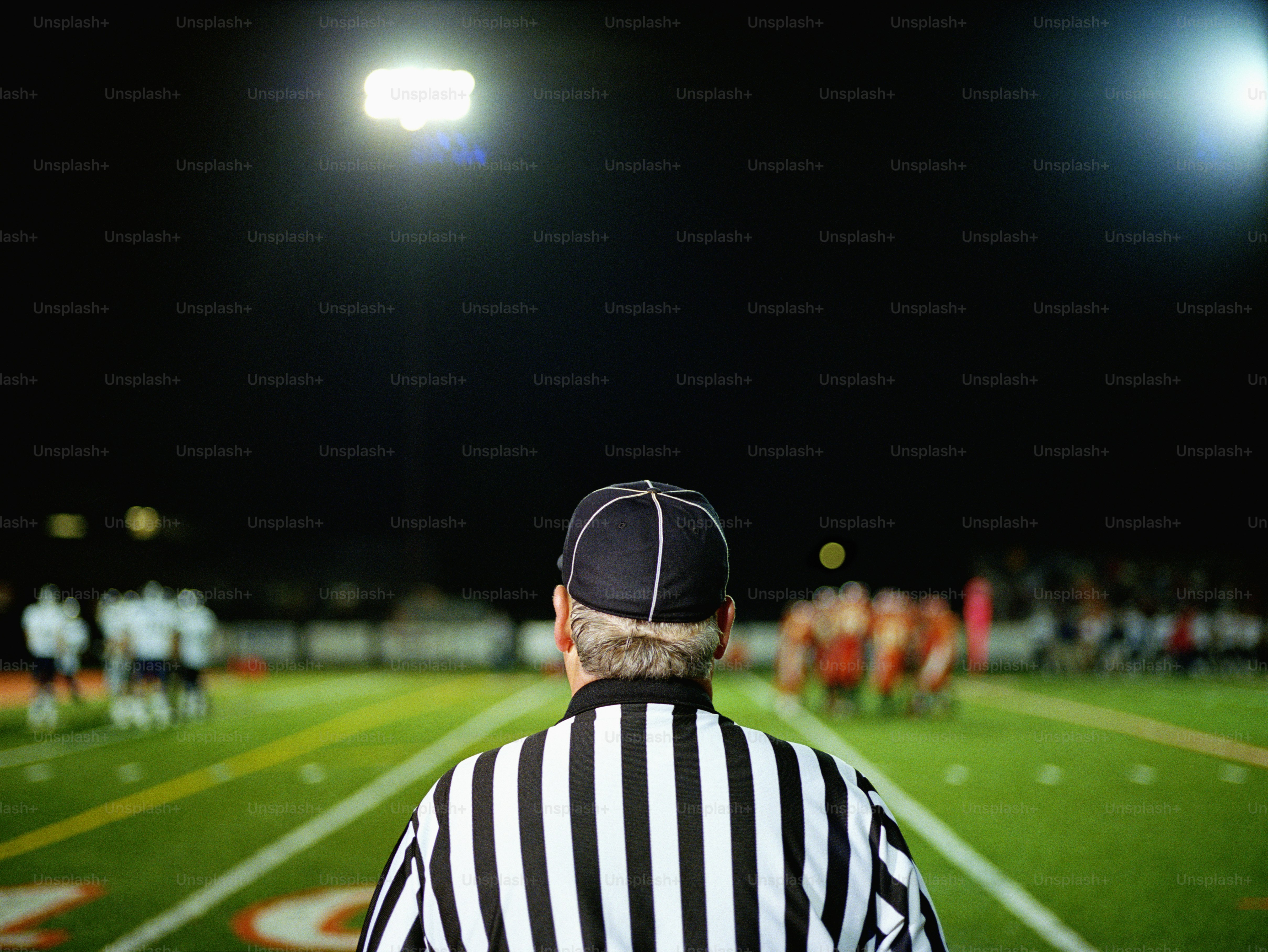 A referee standing on a football field at night photo – Referee Image ...