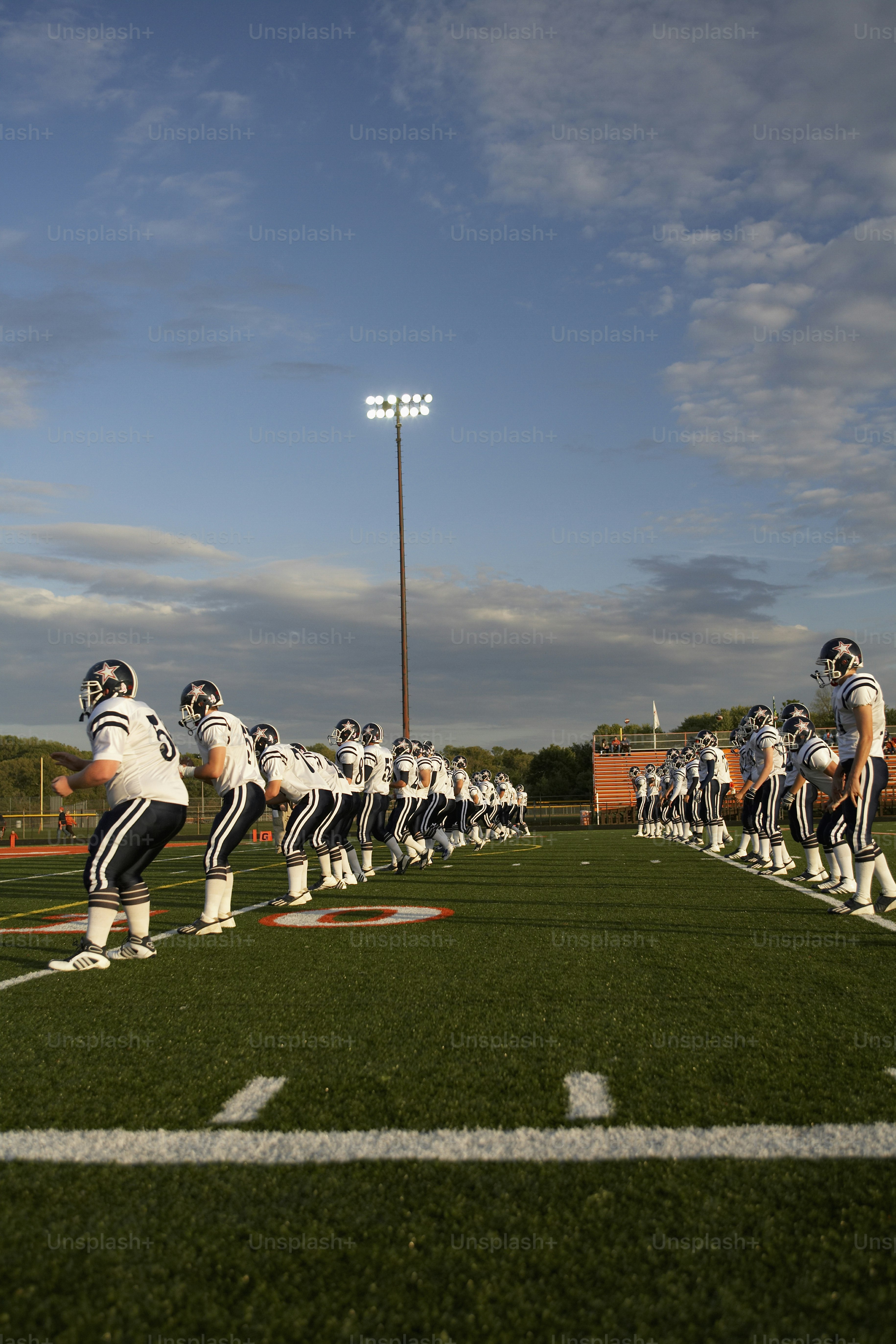 A group of football players standing on top of a field photo – Sport ...