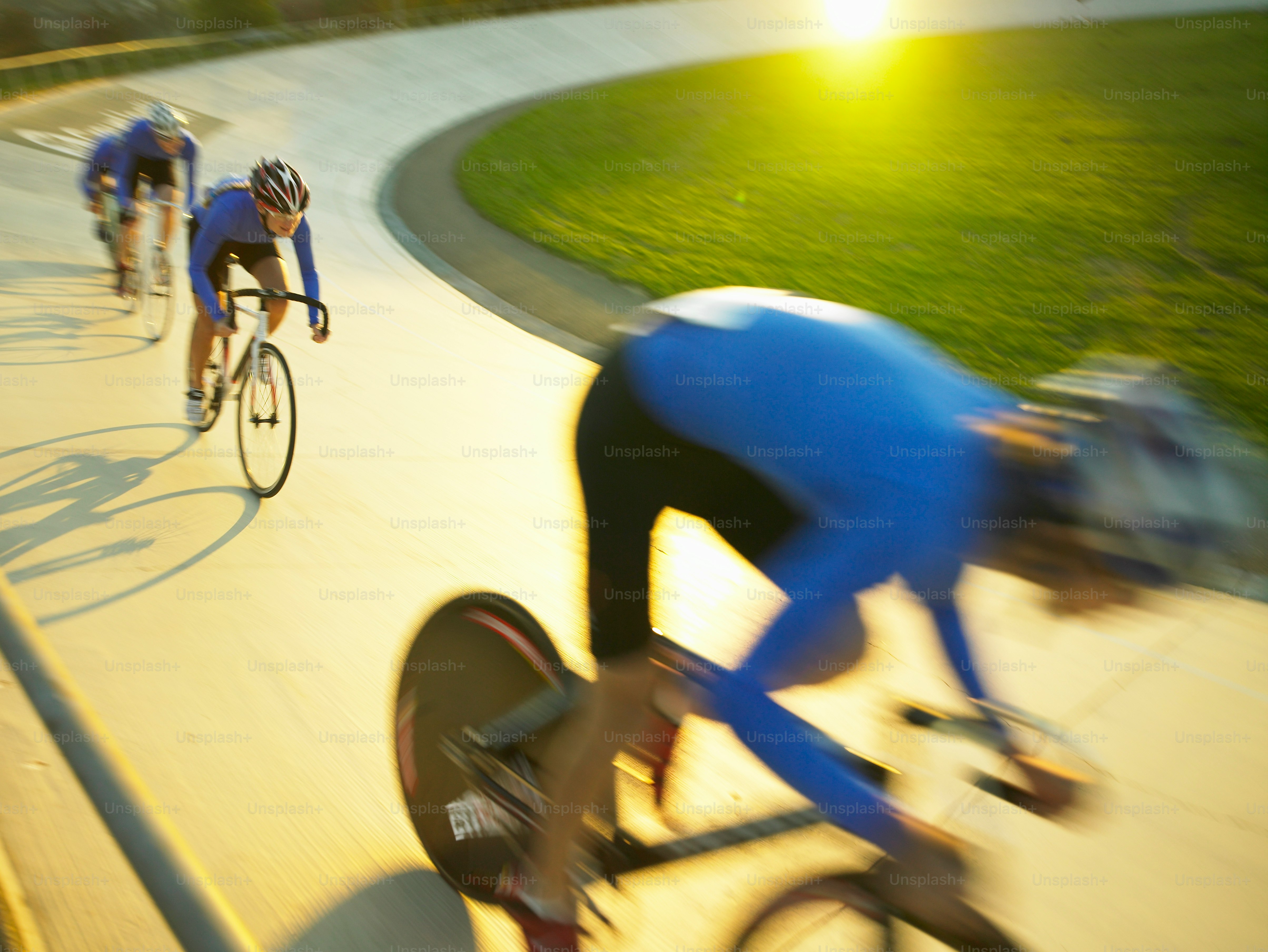 A group of people riding bikes down a street photo – Cycling race Image ...