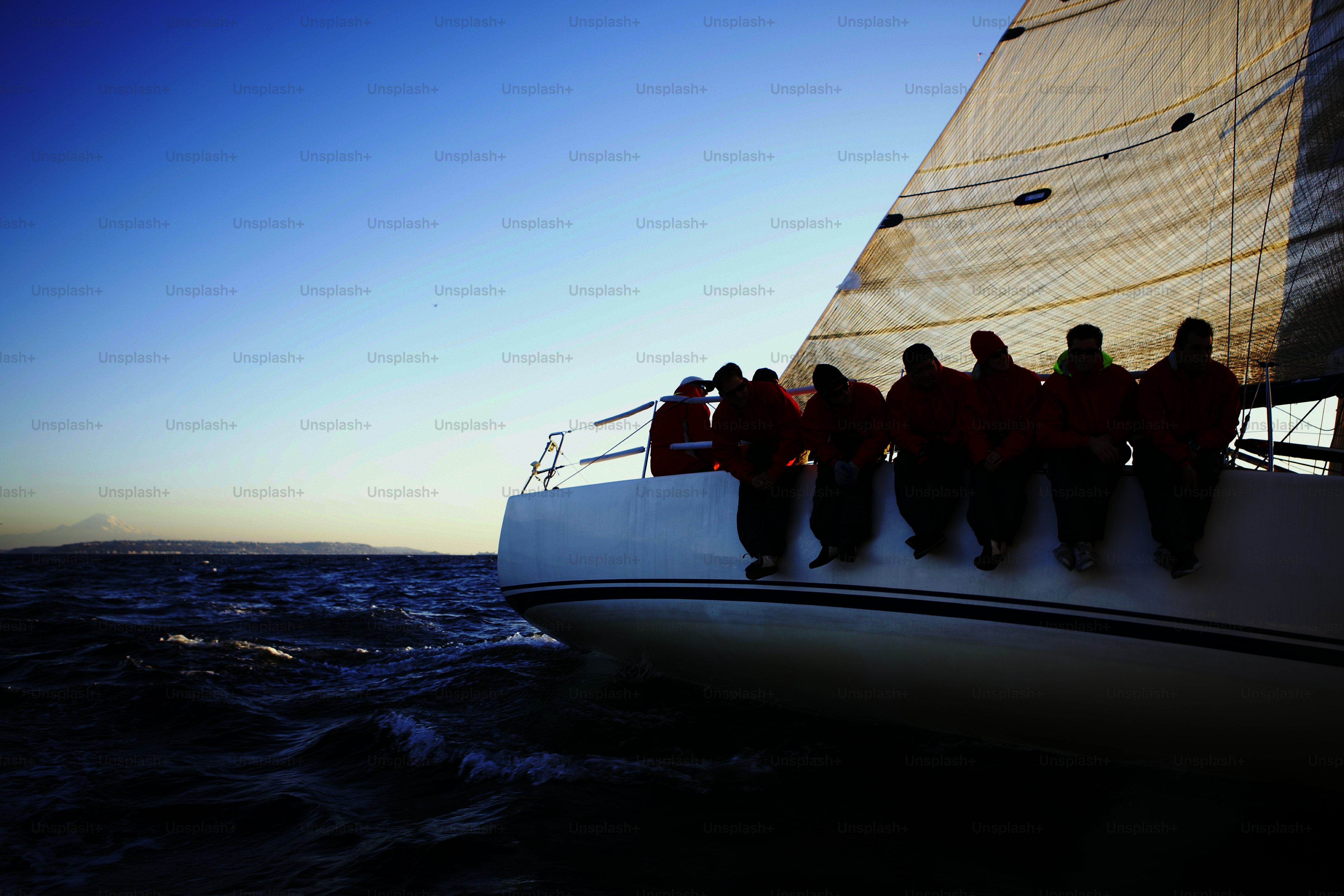 A group of people riding on the back of a sailboat photo – Sail Image ...