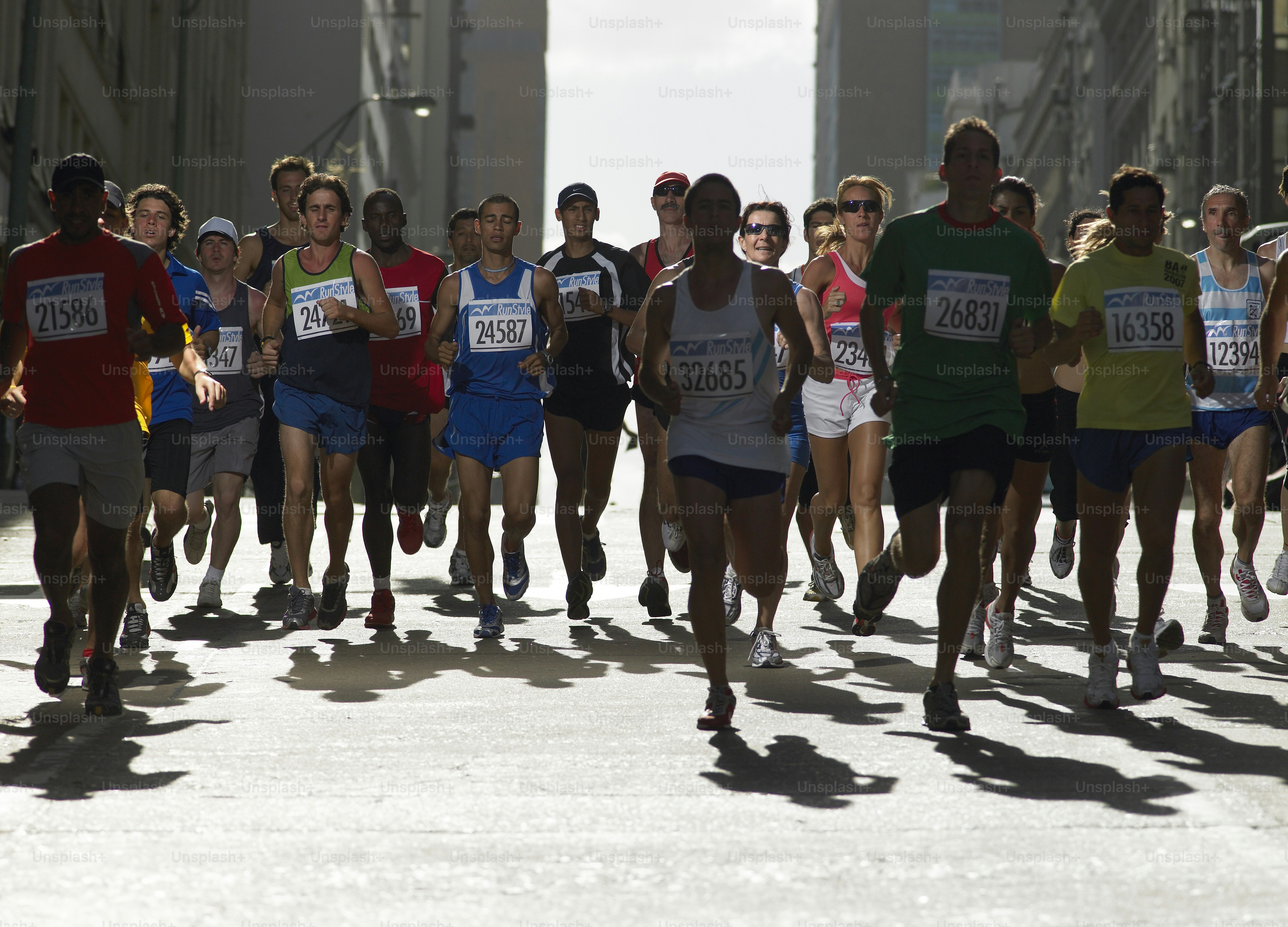 A large group of people running down a street photo – Running Image on ...