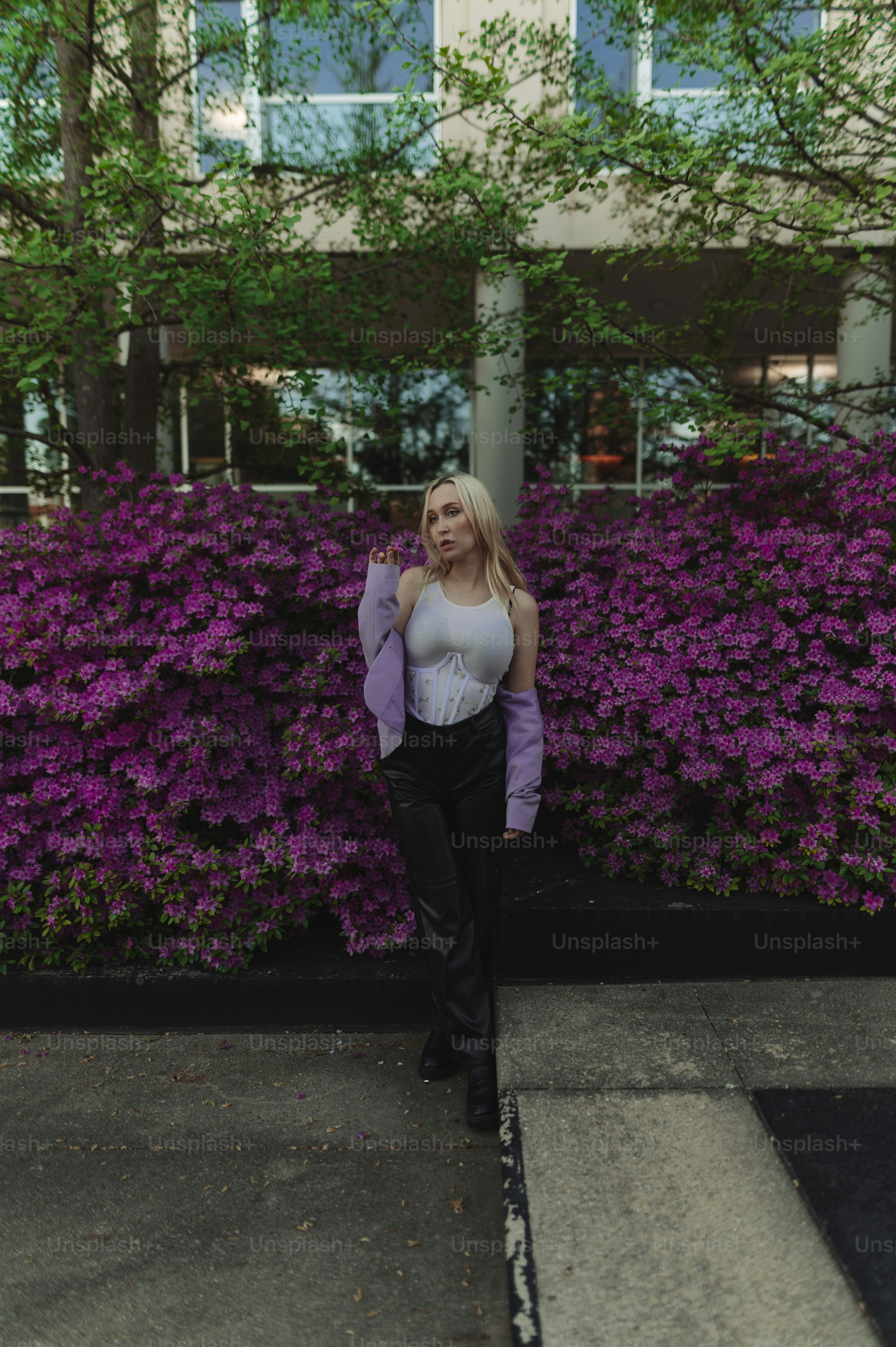 A woman standing in front of purple flowers photo – Fashion Image on ...