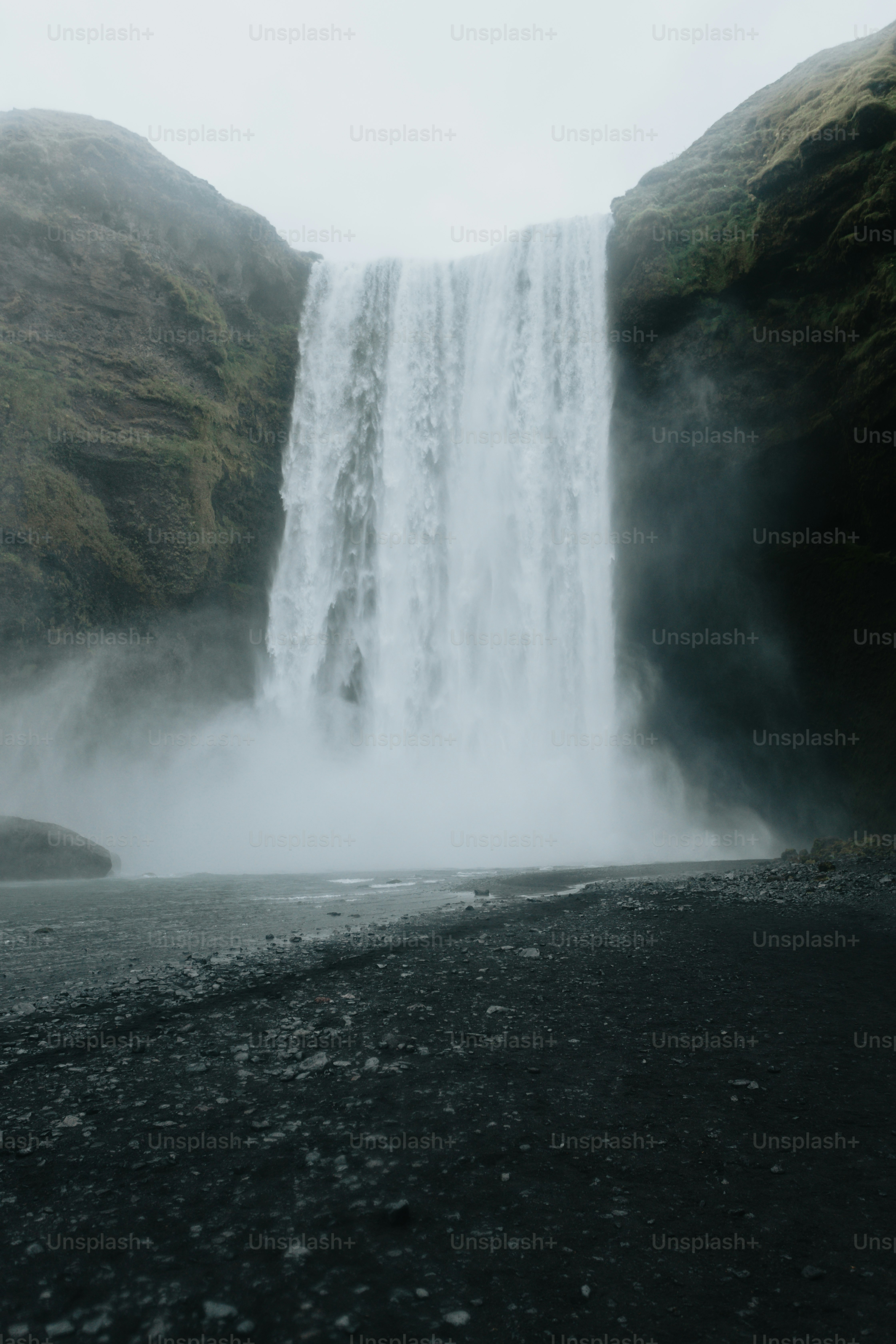 A large waterfall with a large rock in front of it photo – Mountain ...