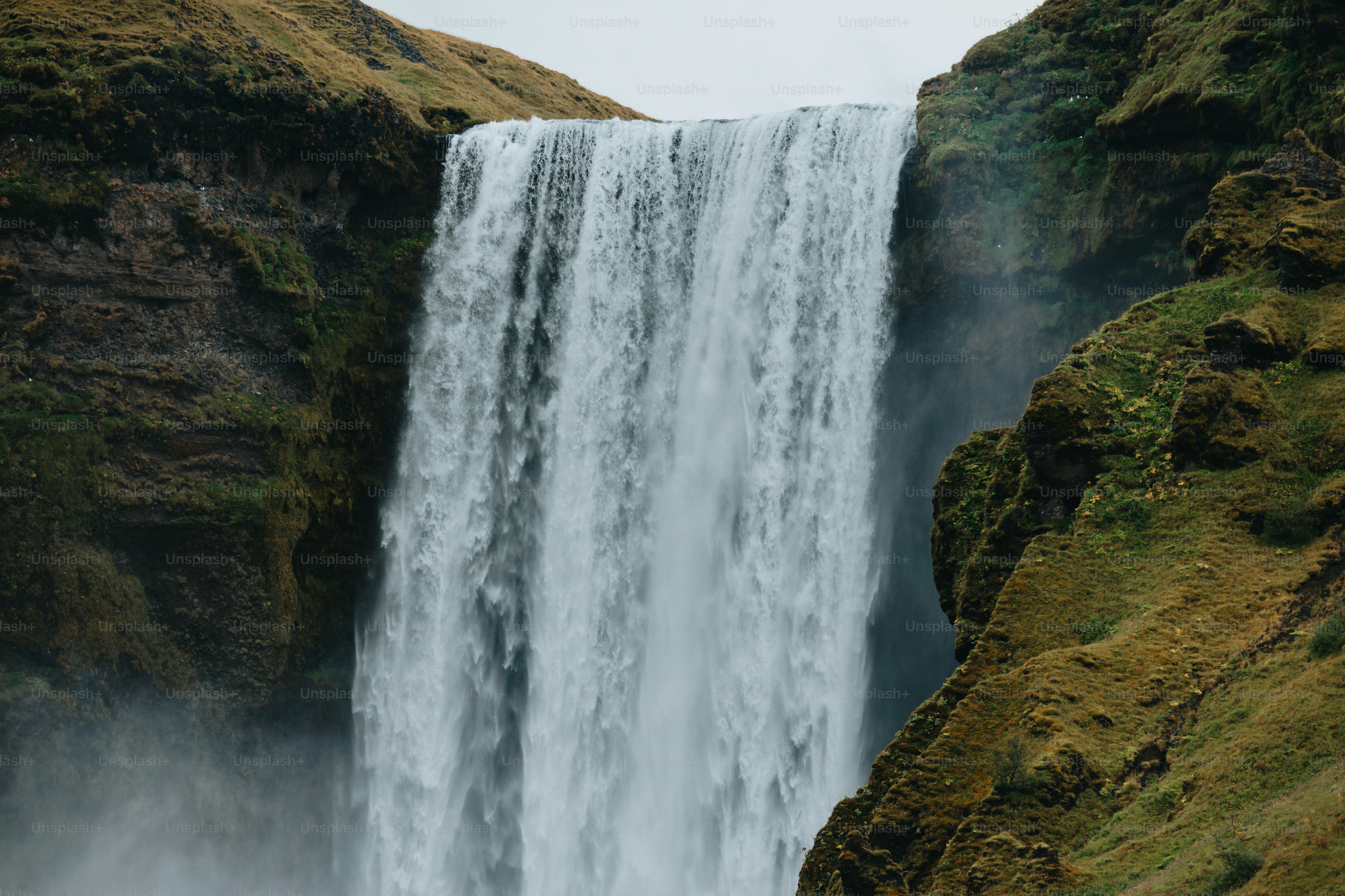 A large waterfall with a large rock in front of it photo – Mountain ...