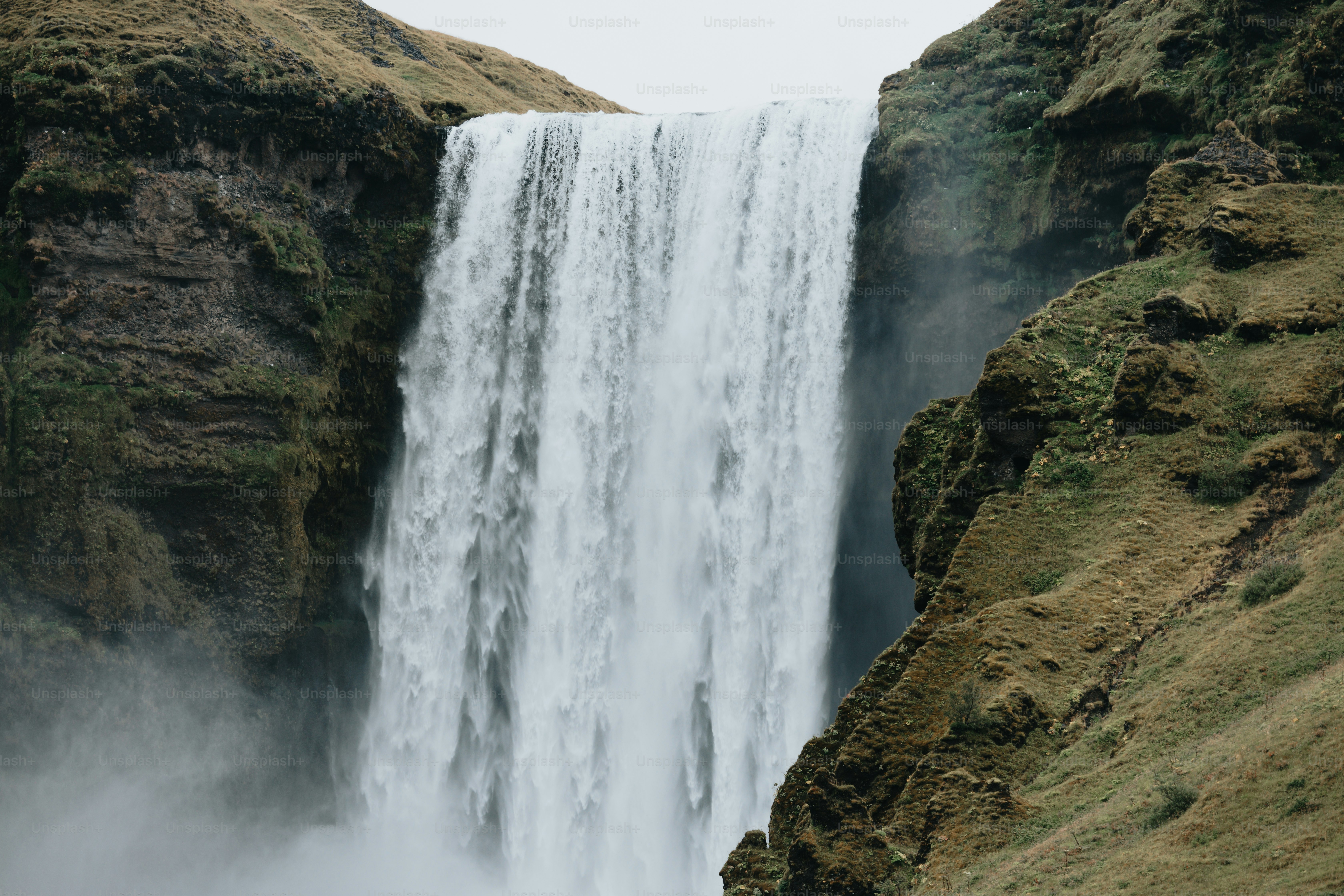 A large waterfall with a man standing in front of it photo – Travel ...