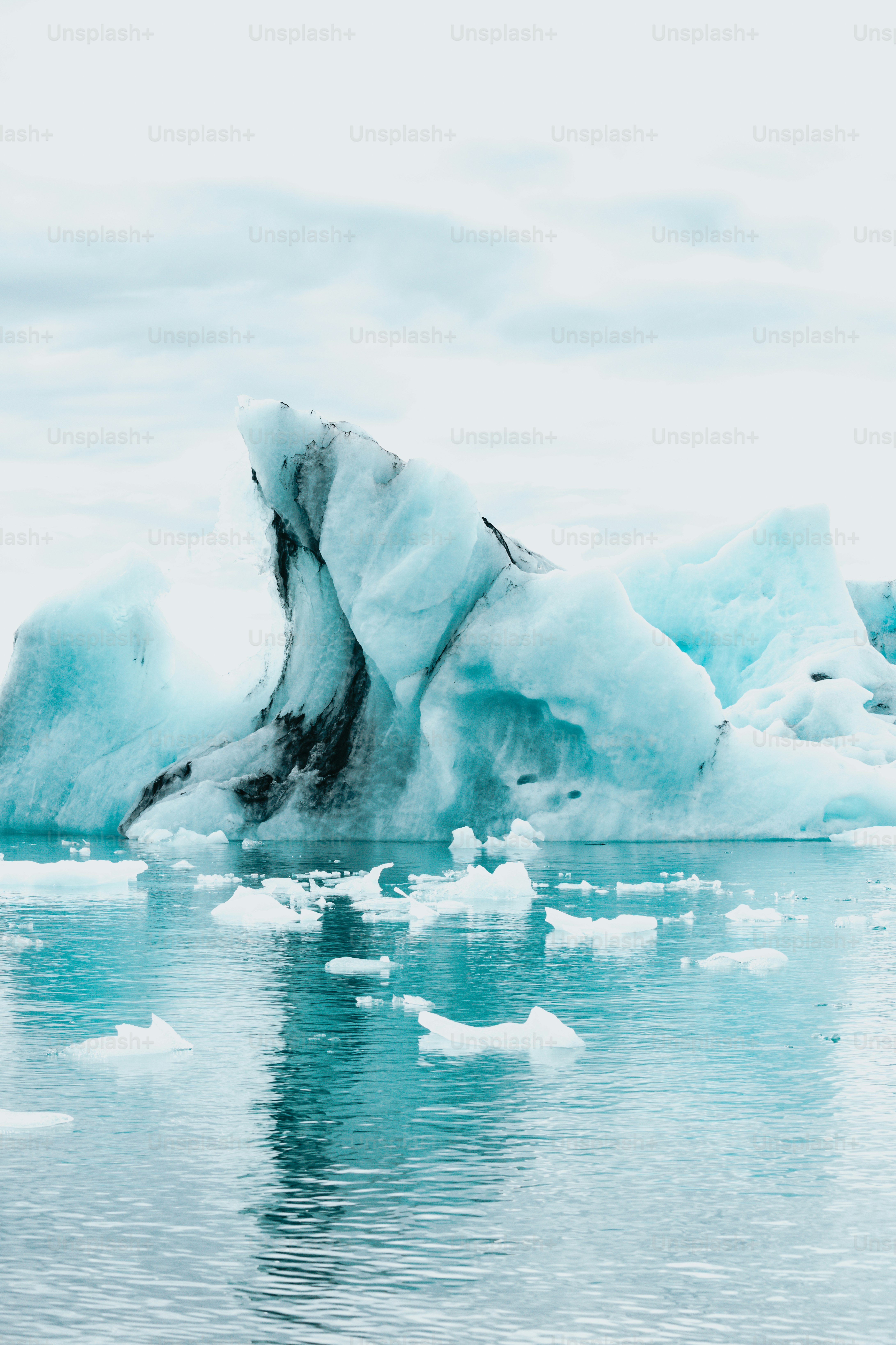 A large iceberg floating in the middle of a body of water photo – Blue ...