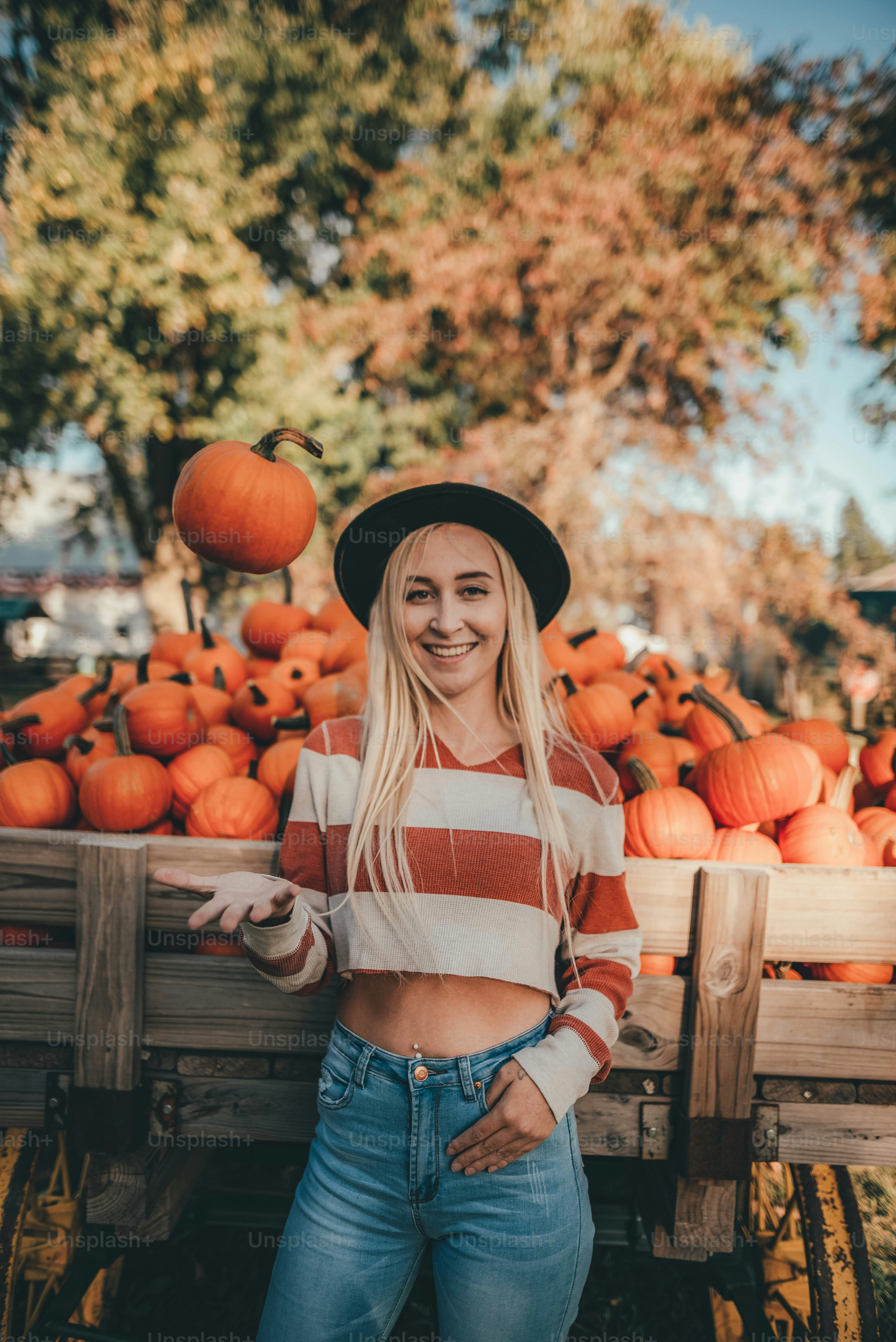 A woman standing in front of a truck full of pumpkins photo – Woman ...