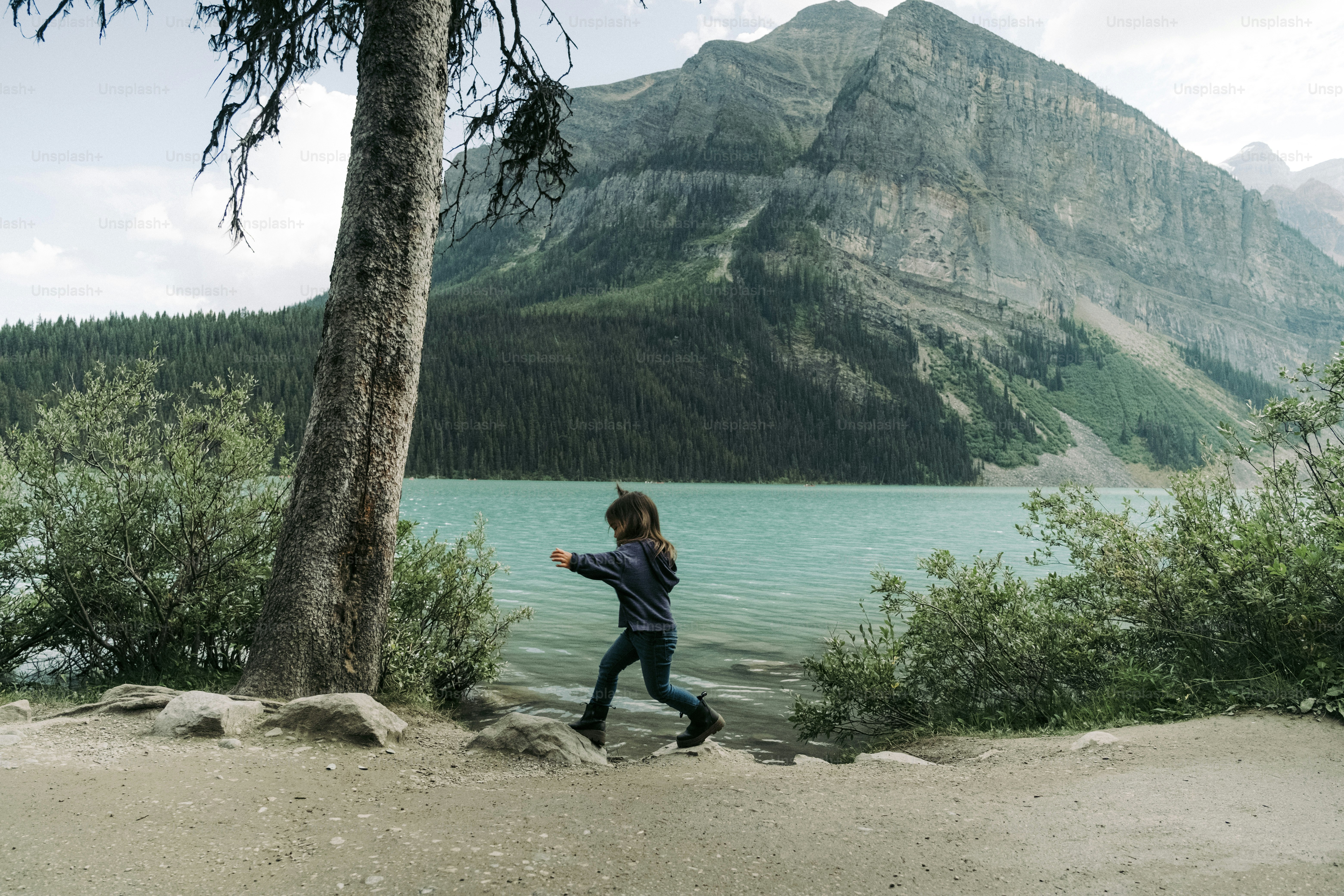 A woman is running near a lake with a mountain in the background photo ...