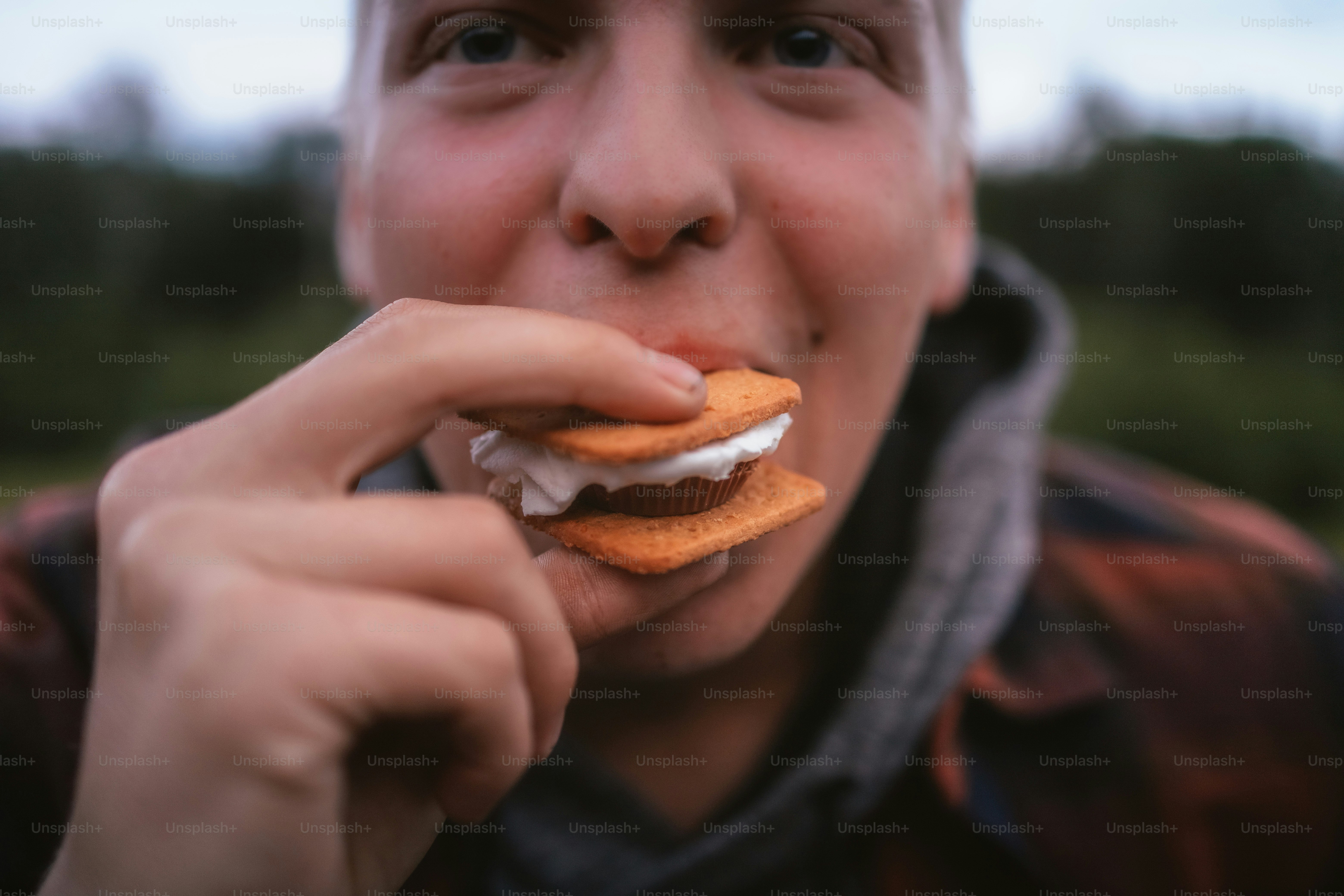 A person eating a pastry with a bite taken out of it photo – Outdoors ...