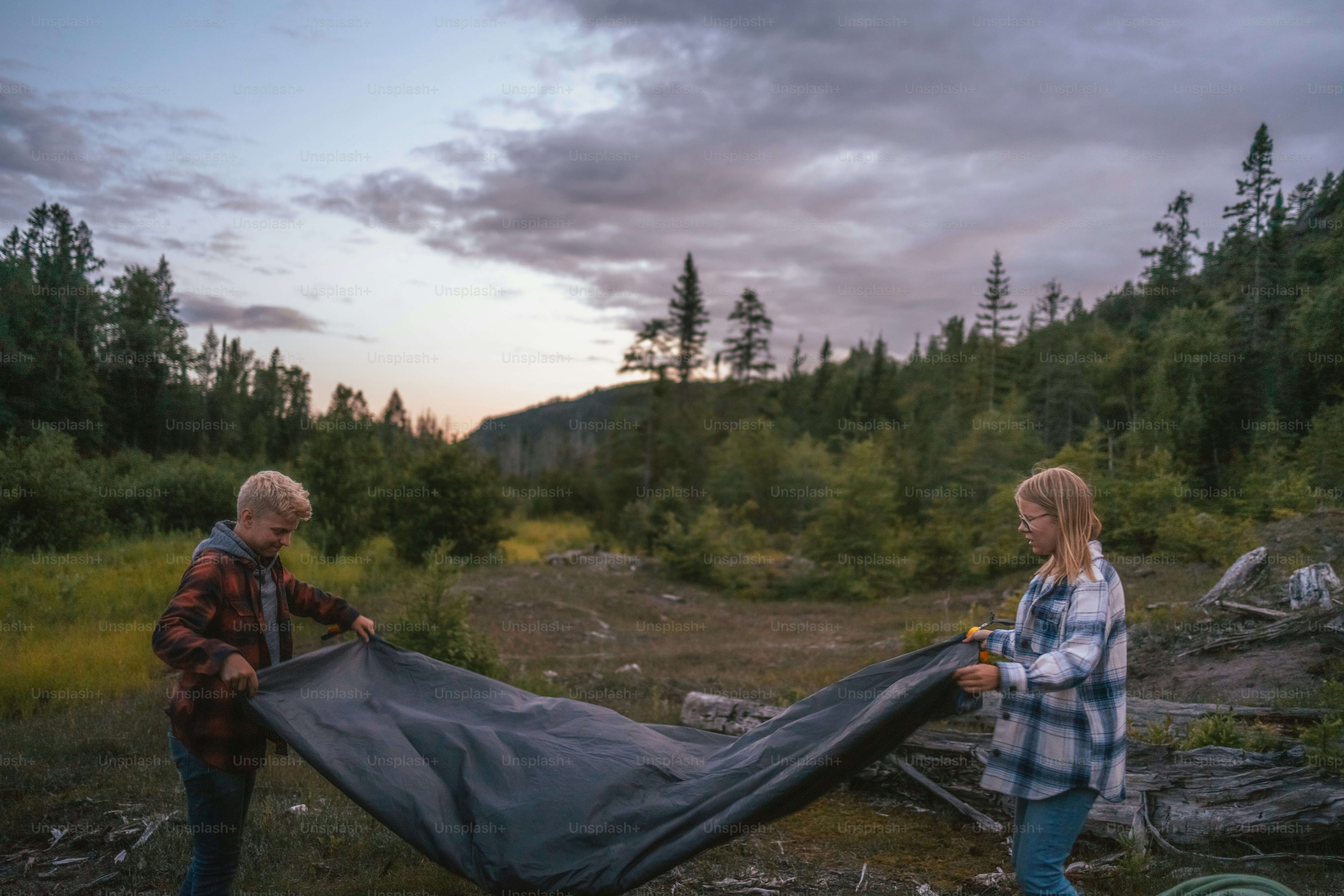 A couple of people standing next to a tarp photo – Wilderness Image on ...