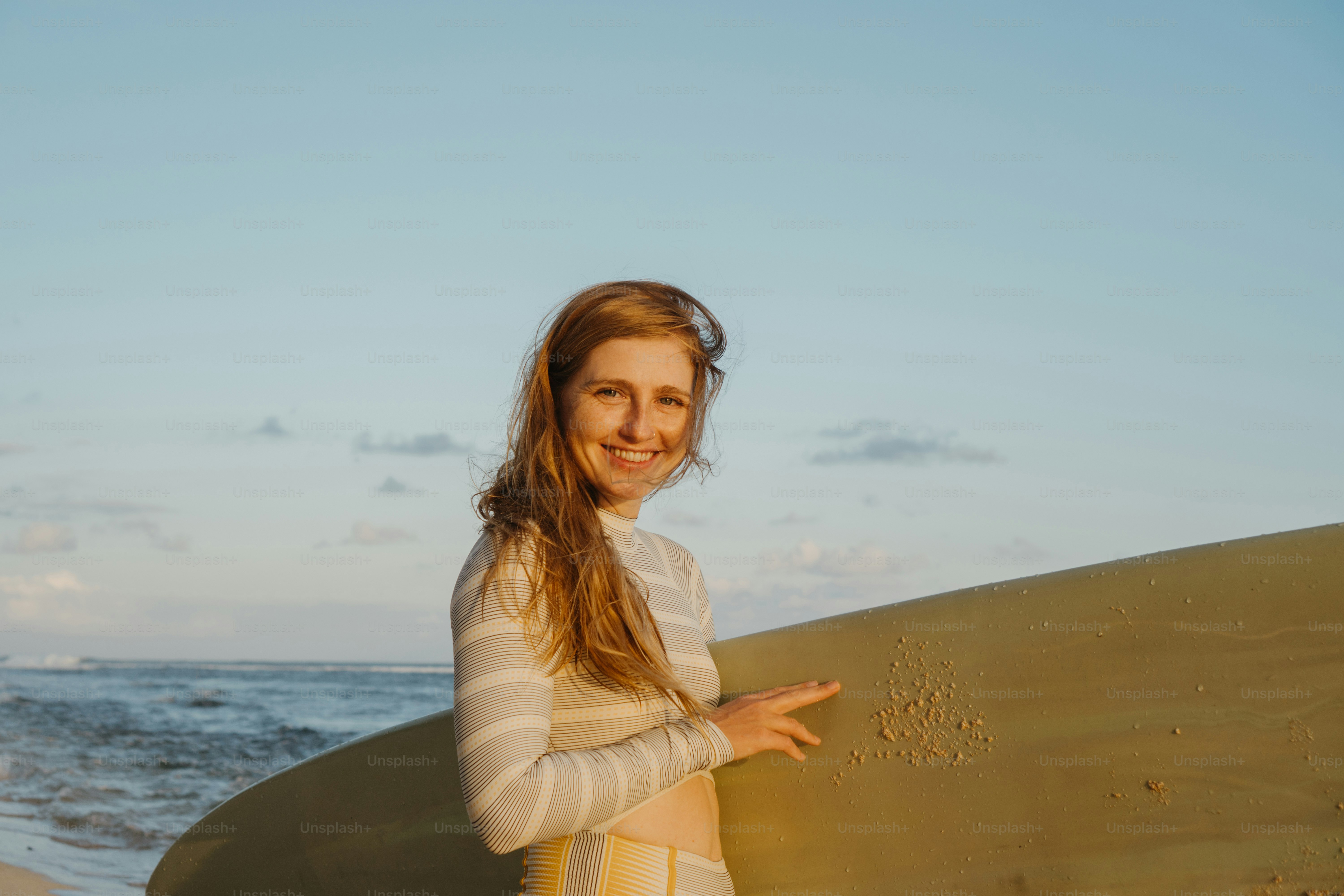 A woman standing in the ocean holding a surfboard photo – Surfing Image ...