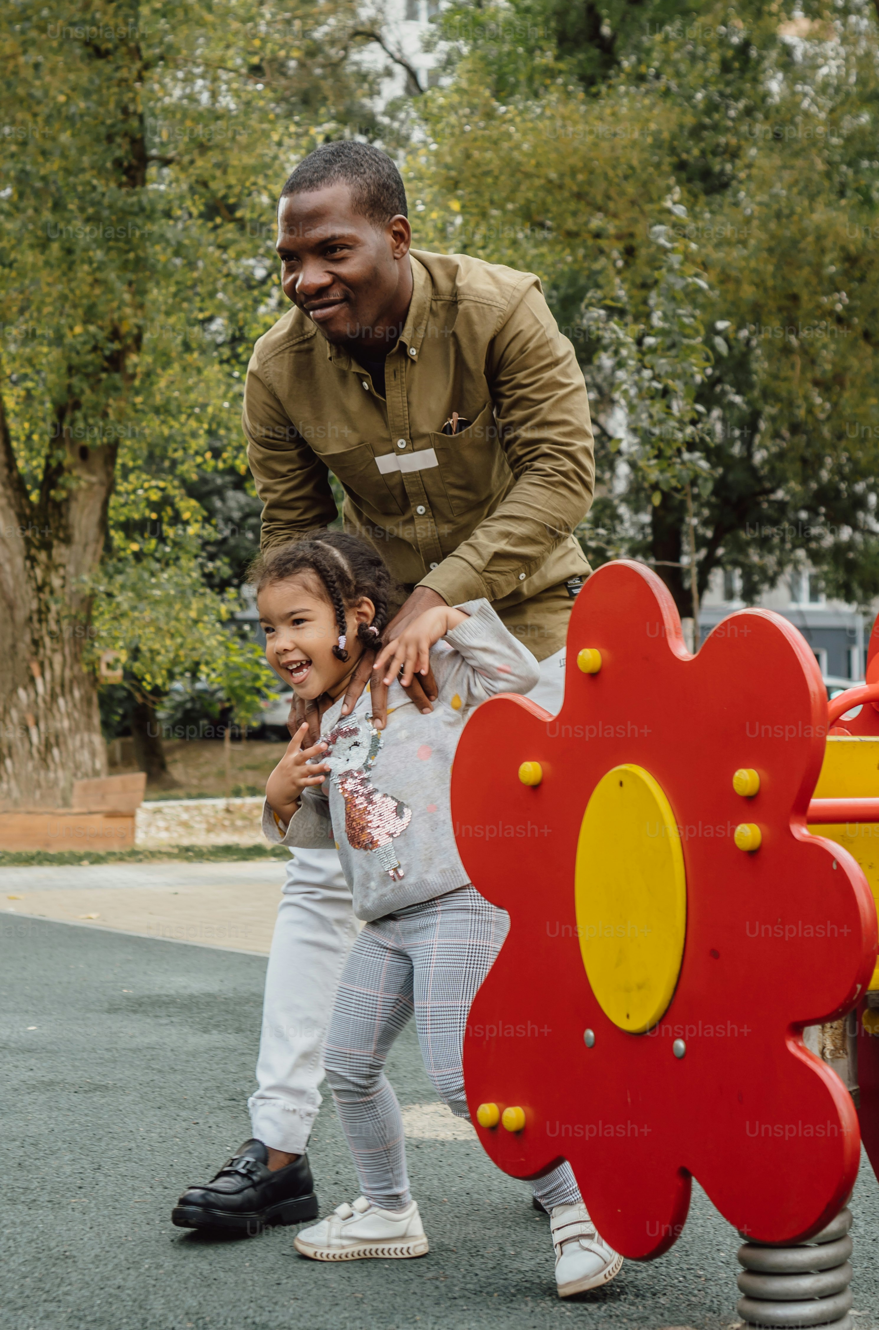 A man helping a little girl play on a playground photo – Play park ...
