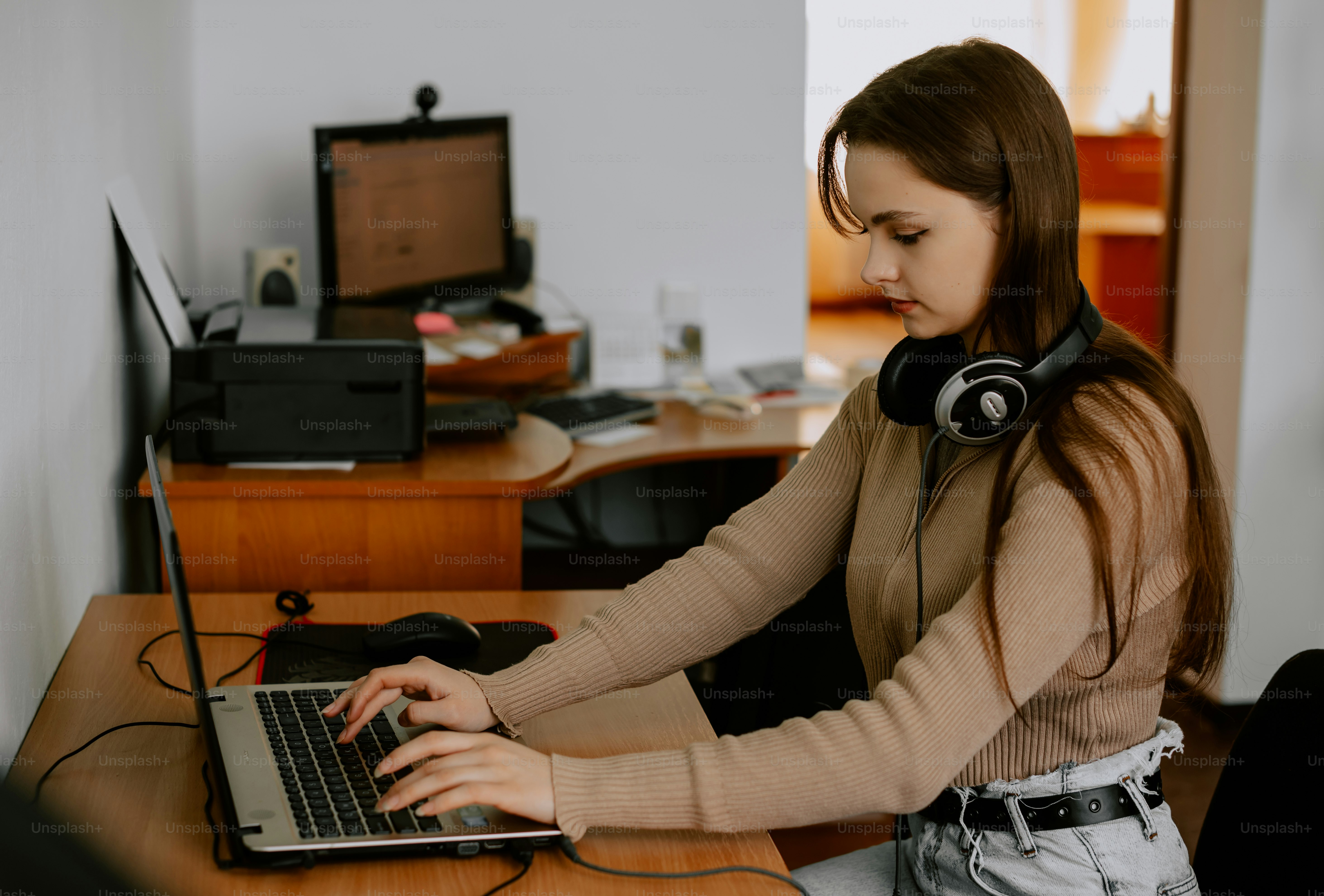 A woman sitting in front of a laptop computer wearing headphones photo ...