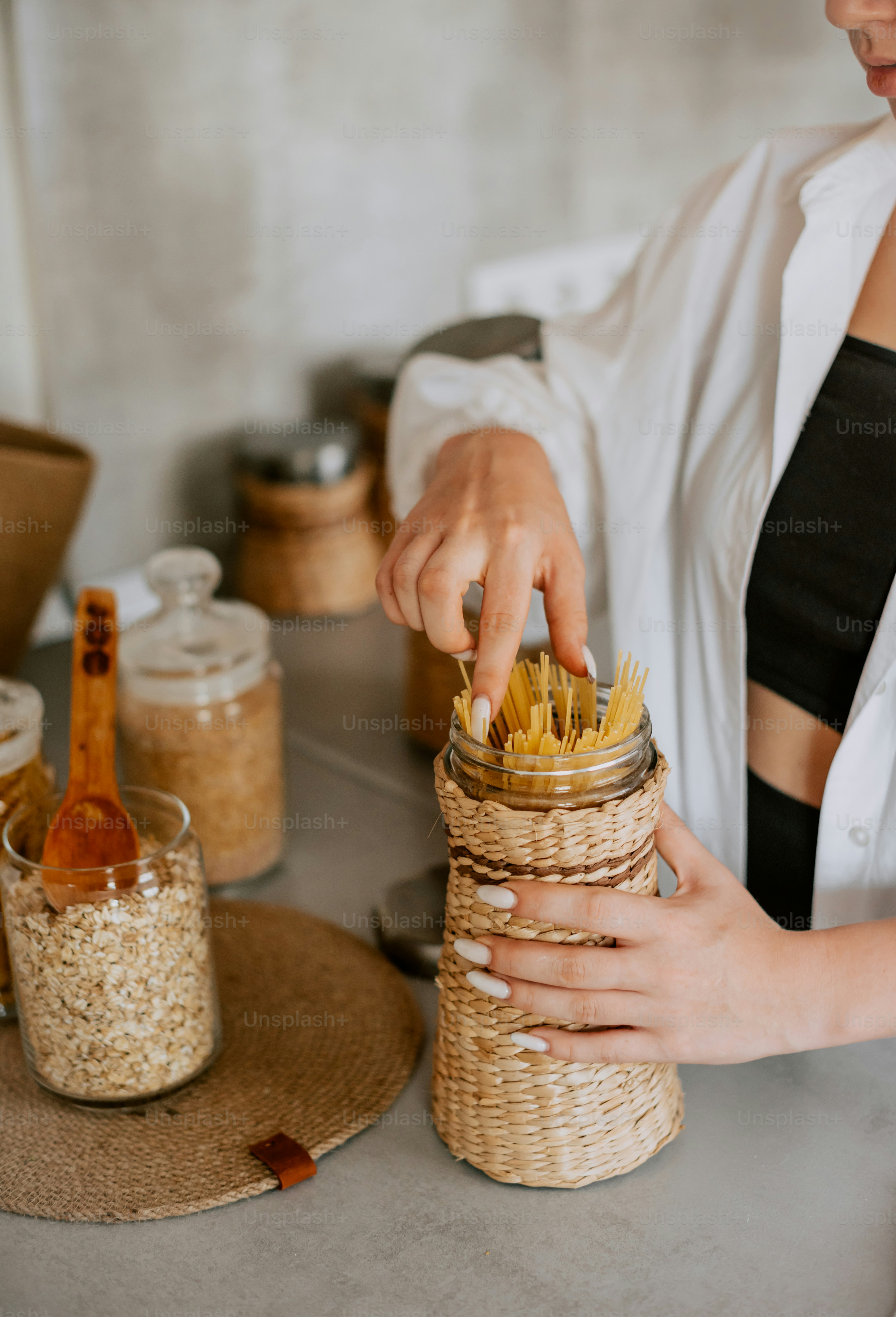 A woman putting food in a jar on top of a counter photo – Food storage ...