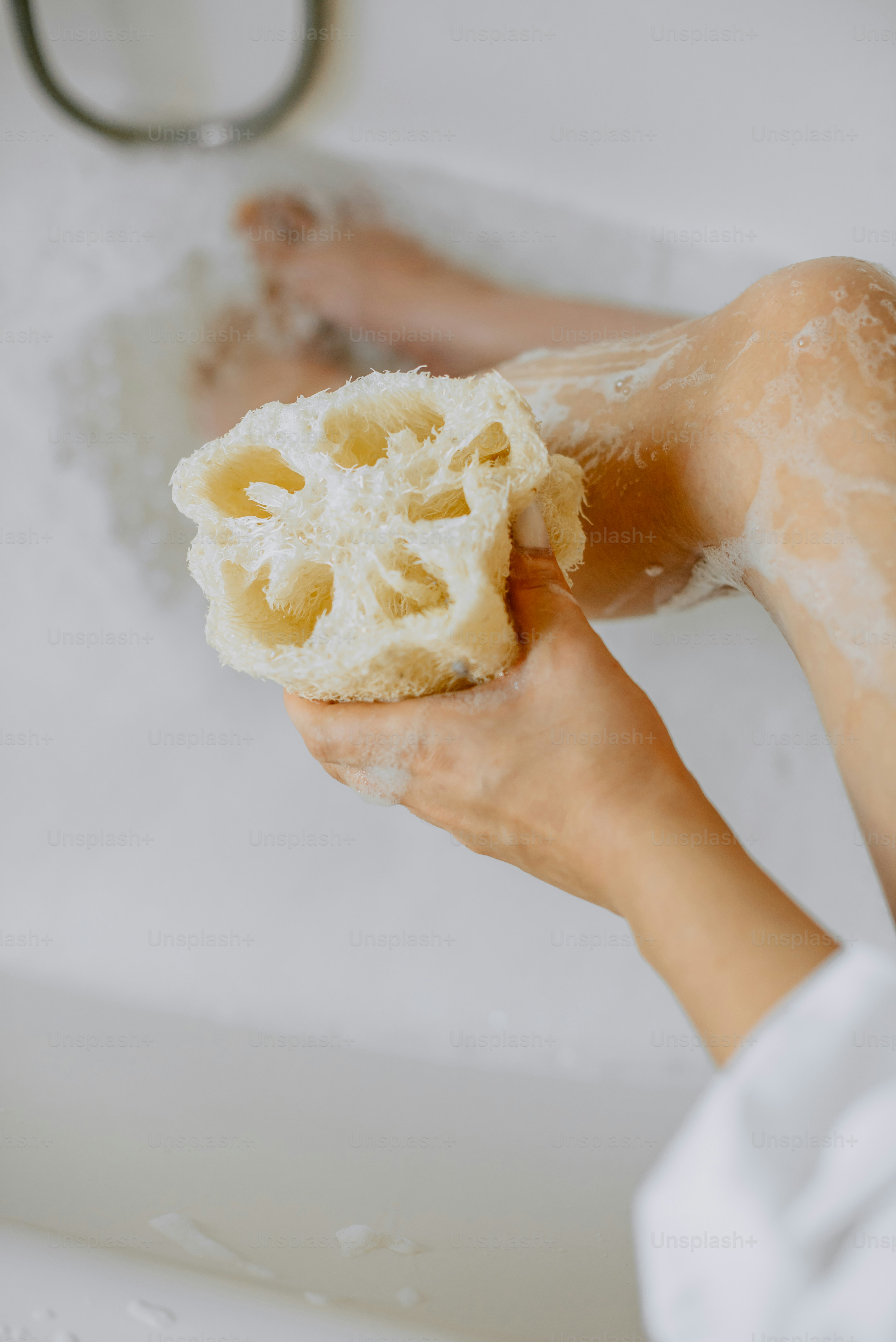A person holding a sponge in a bathtub photo – Body wash Image on Unsplash